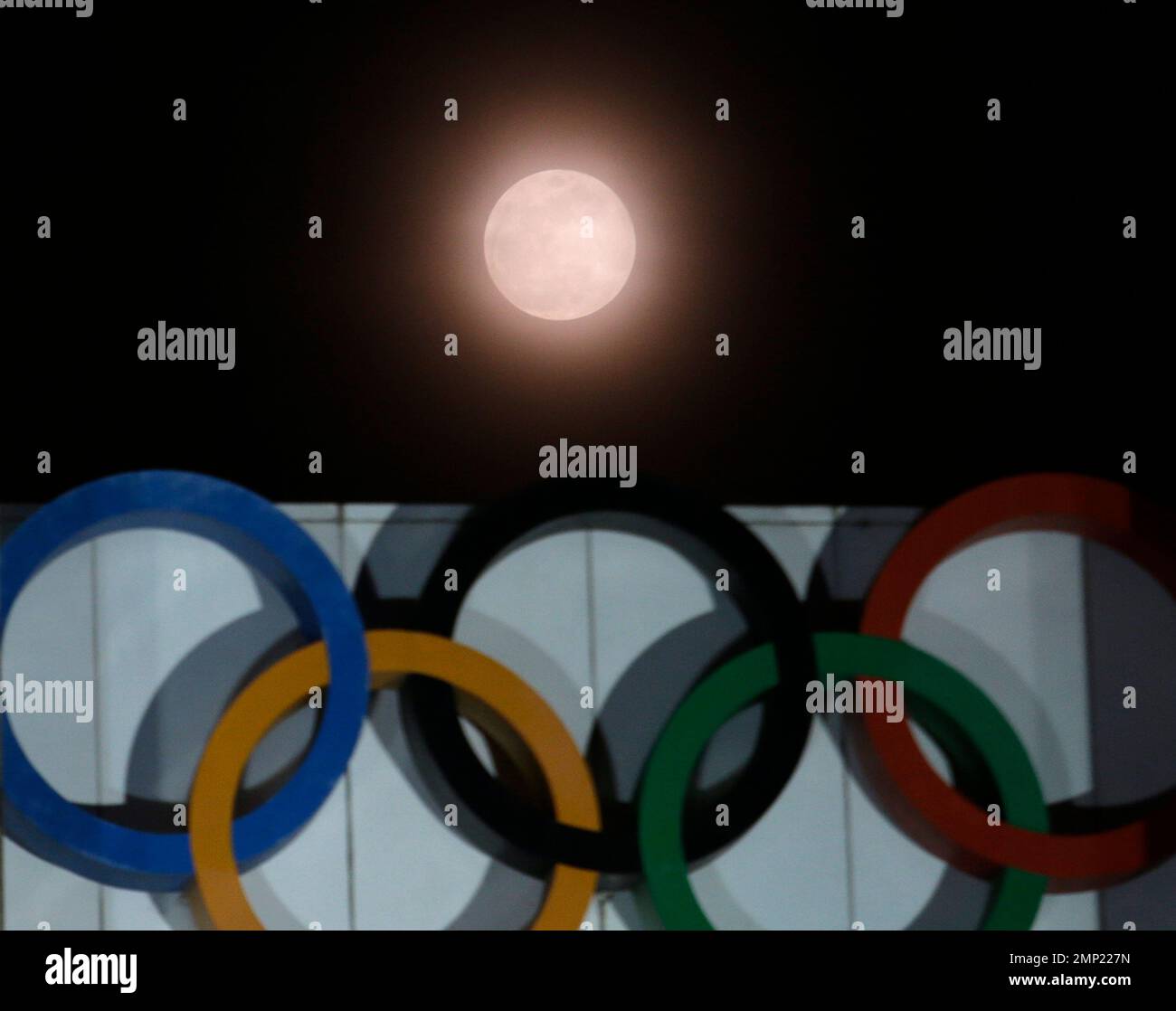 The full moon is seen over the Olympic rings on display at the Peace ...