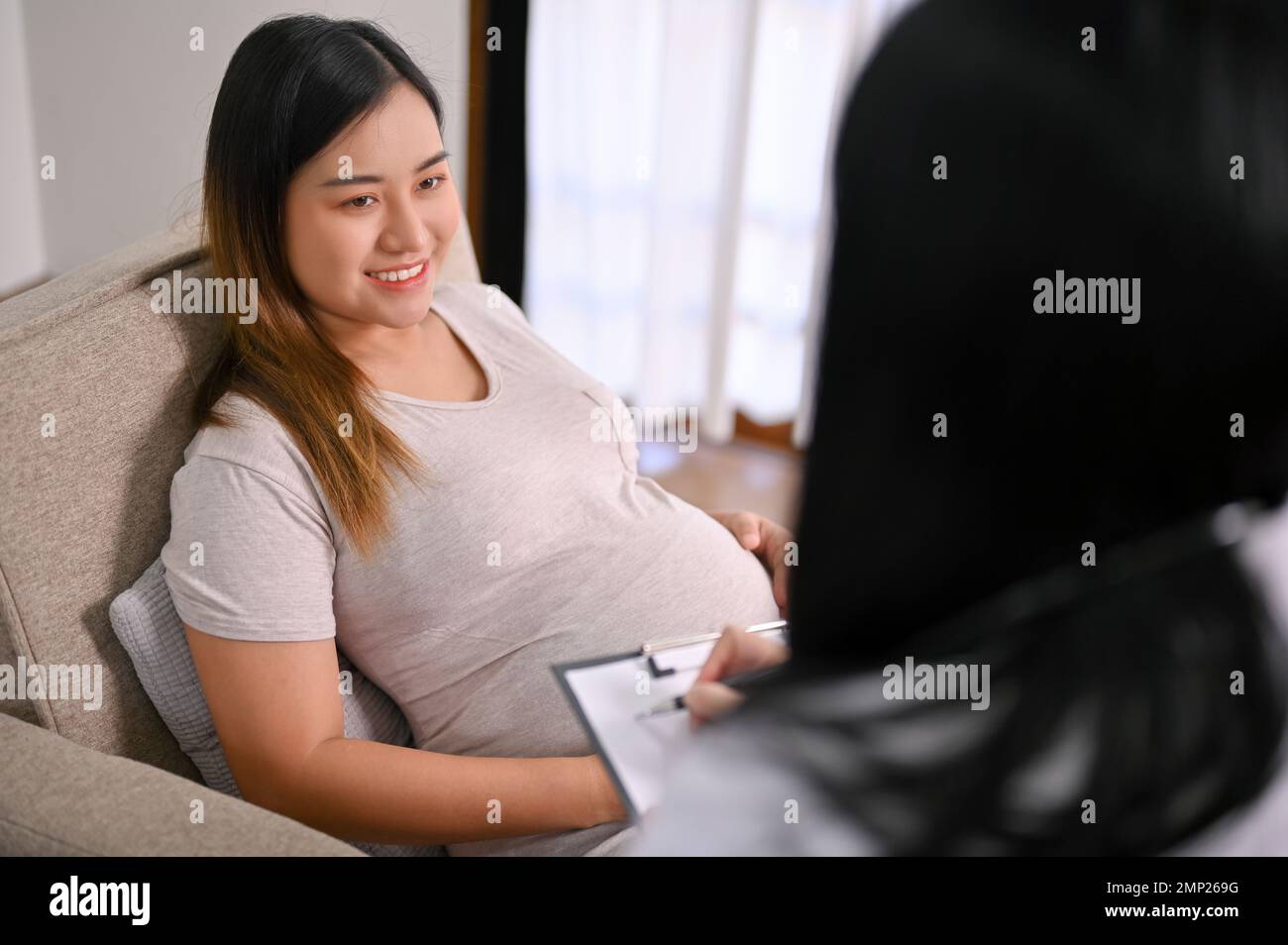 Happy Asian pregnant woman has an appointment with her doctor to get a ...