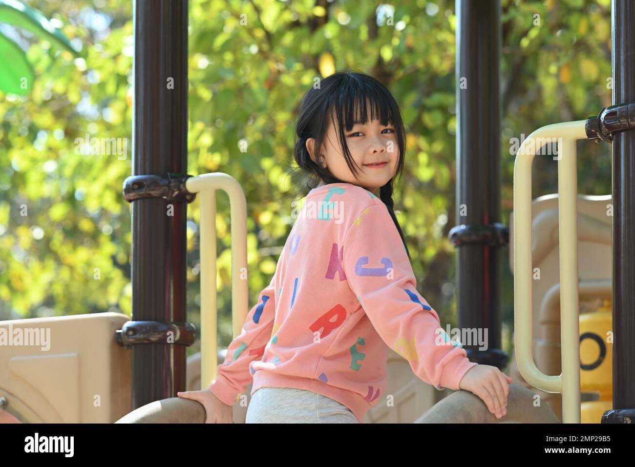 Adorable Asian Girl Having Fun On Playground In Public Park Surrounded