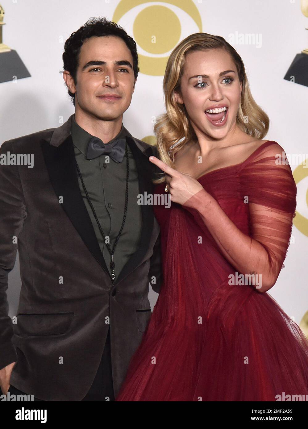 Zac Posen, left, and Miley Cyrus pose in the press room at the 60th ...