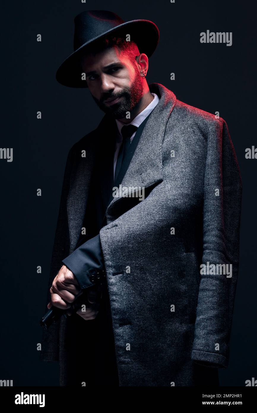 Gangster, portrait and holding gun on studio background in dark secret ...