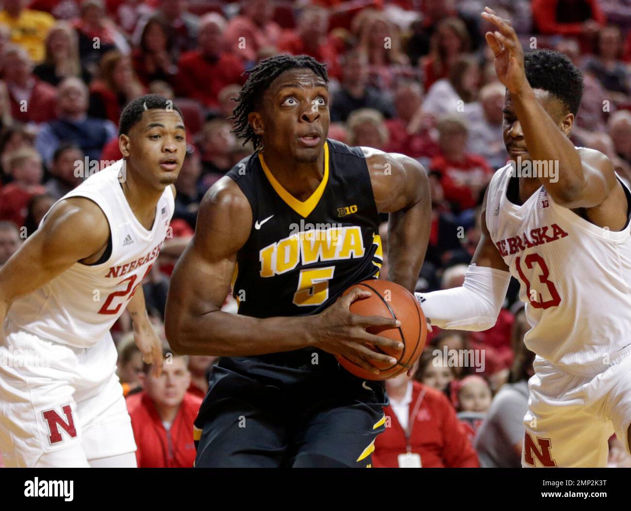 Iowa's Tyler Cook (5) goes to the basket between Nebraska's Anton Gill ...