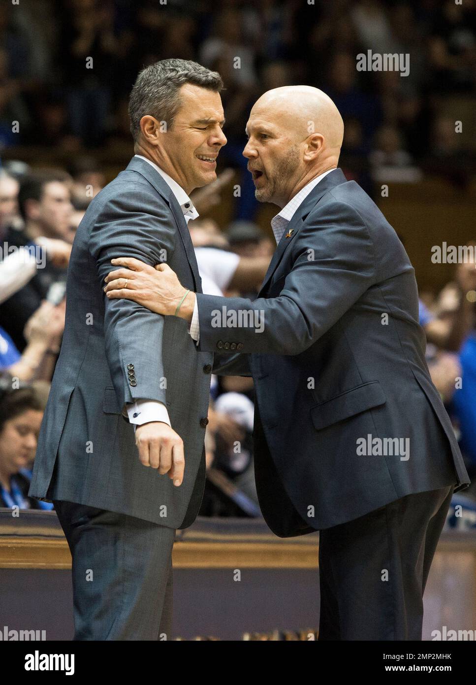 Virginia Head Coach Tony Bennett, left, is held away from the court by ...