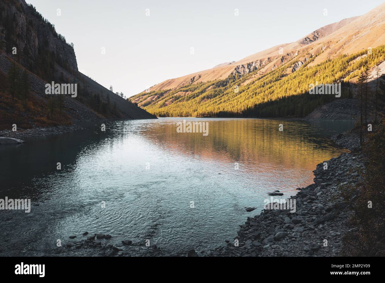 Alpine lake Shavlinskoe in the shade between rocks and forest in the ...