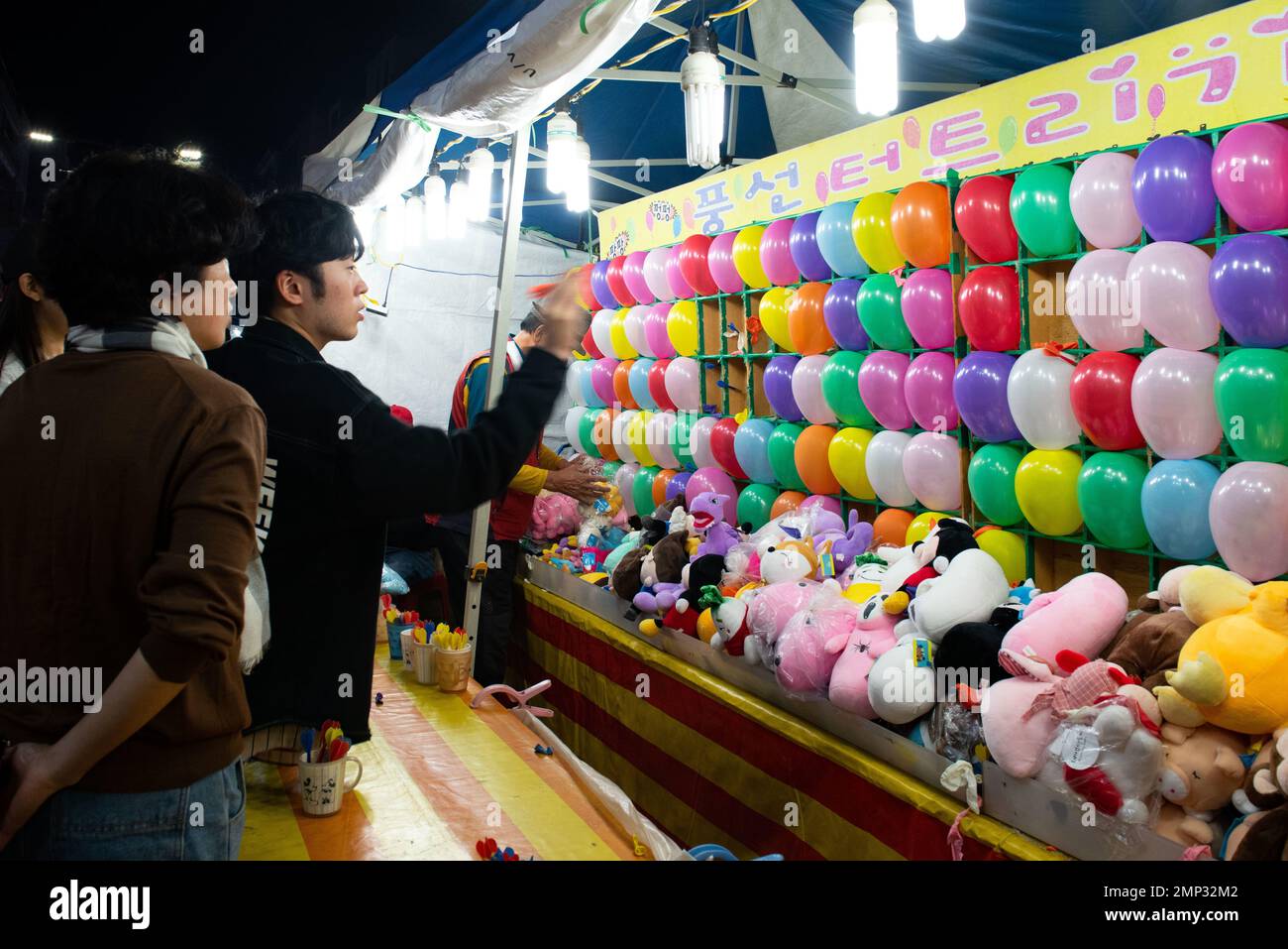 Attendees play a balloon dart game during the 19th Republic of Korea ...
