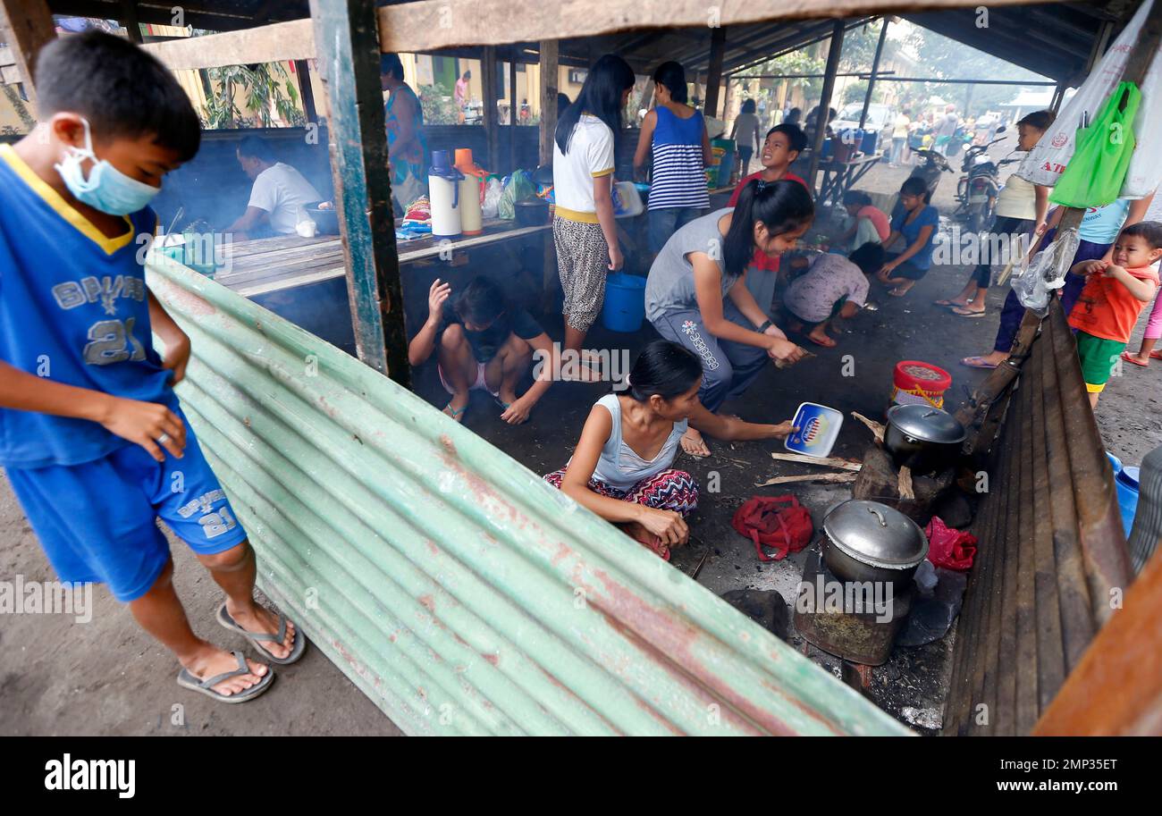 Evacuees cook their meals at a common kitchen in an evacuation center ...