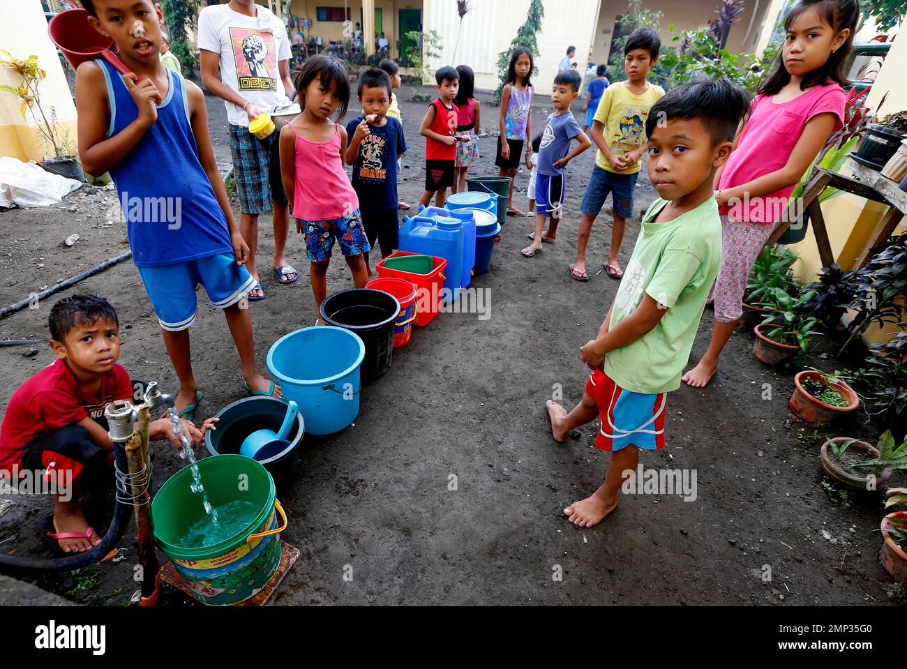 Children line up to collect water at an evacuation center in Miisi ...
