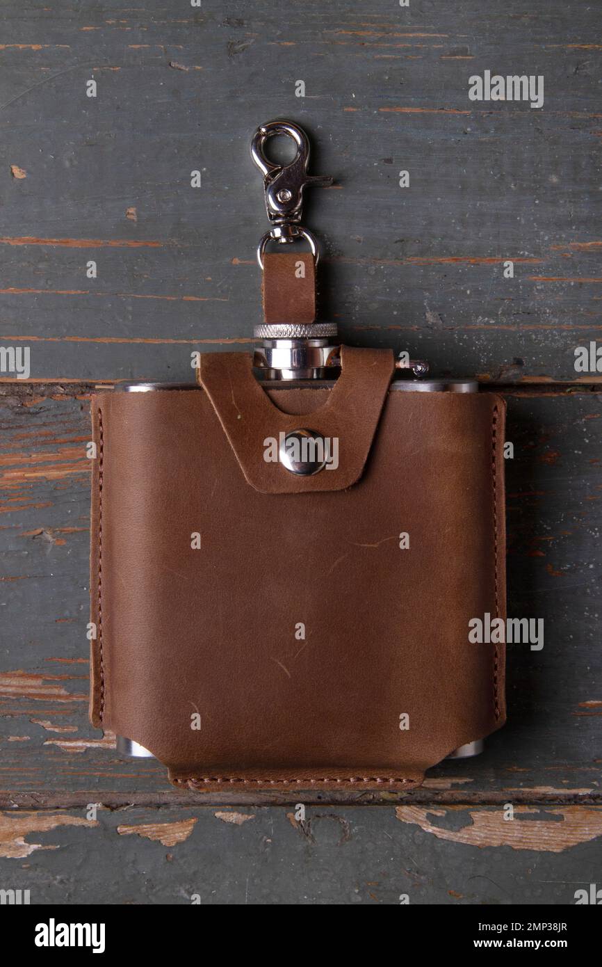 Hip flask in leather case on painted wooden timber Stock Photo - Alamy