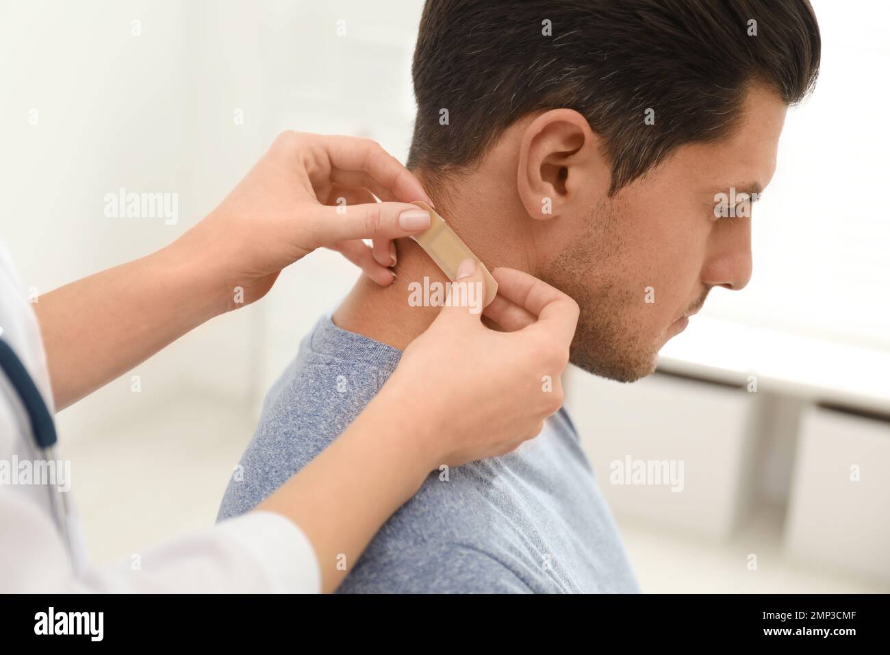 Doctor putting sticking plaster onto man's neck indoors Stock Photo - Alamy
