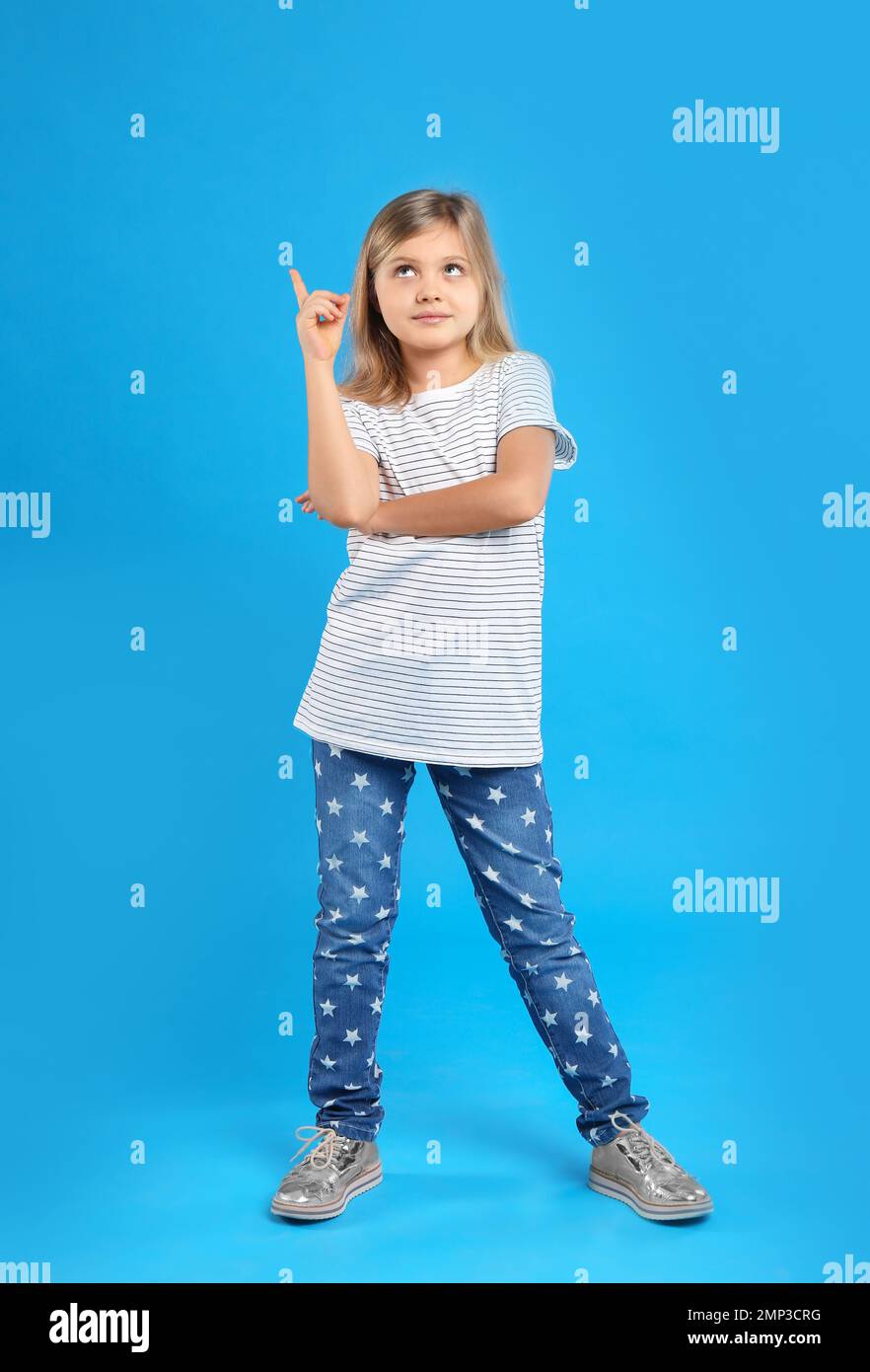 Cute little girl on light blue background Stock Photo - Alamy