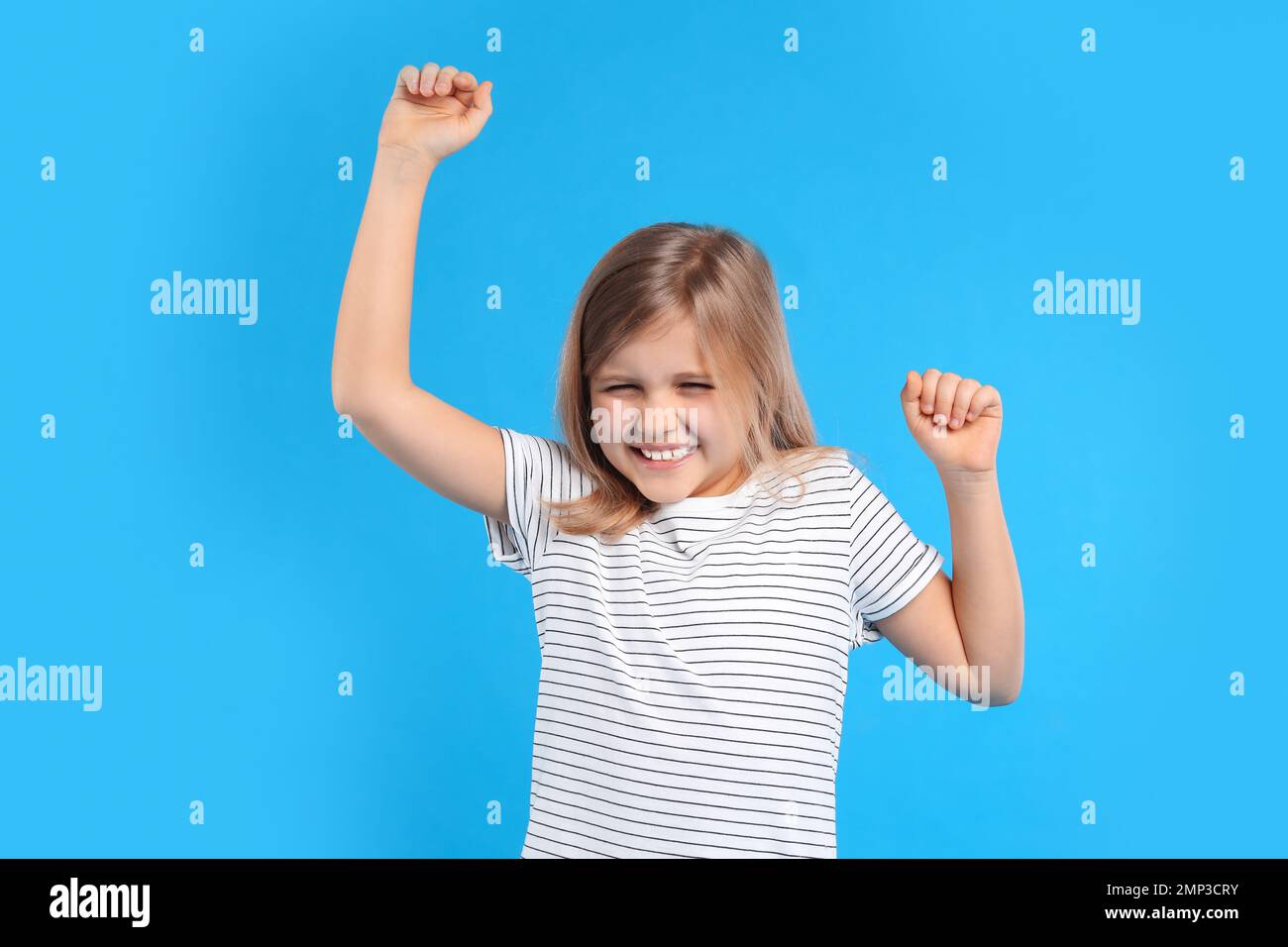 Excited little girl on light blue background Stock Photo - Alamy