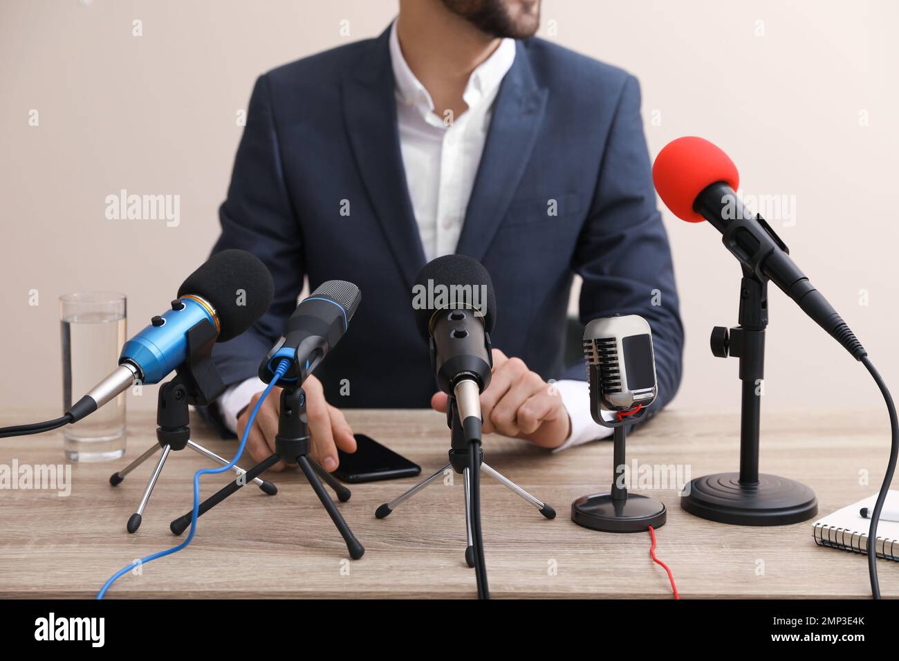 Businessman giving interview at table with microphones, closeup ...