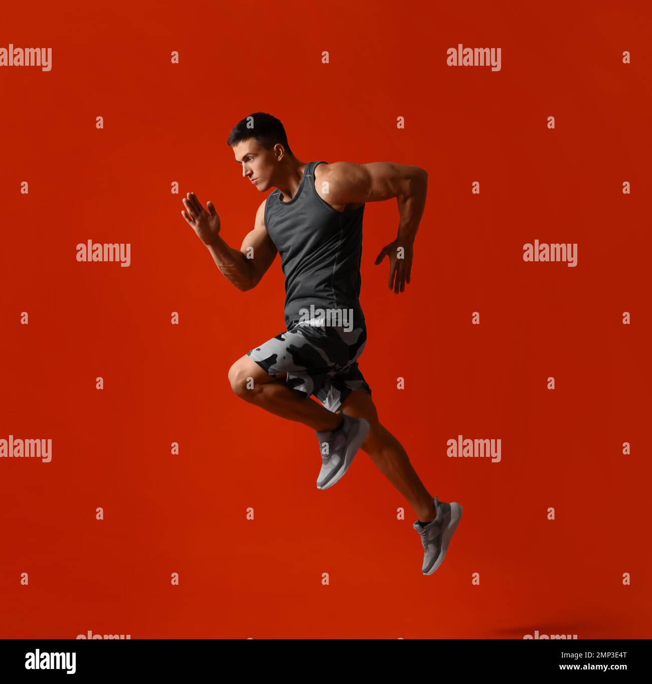 Athletic young man running on red background, side view Stock Photo - Alamy