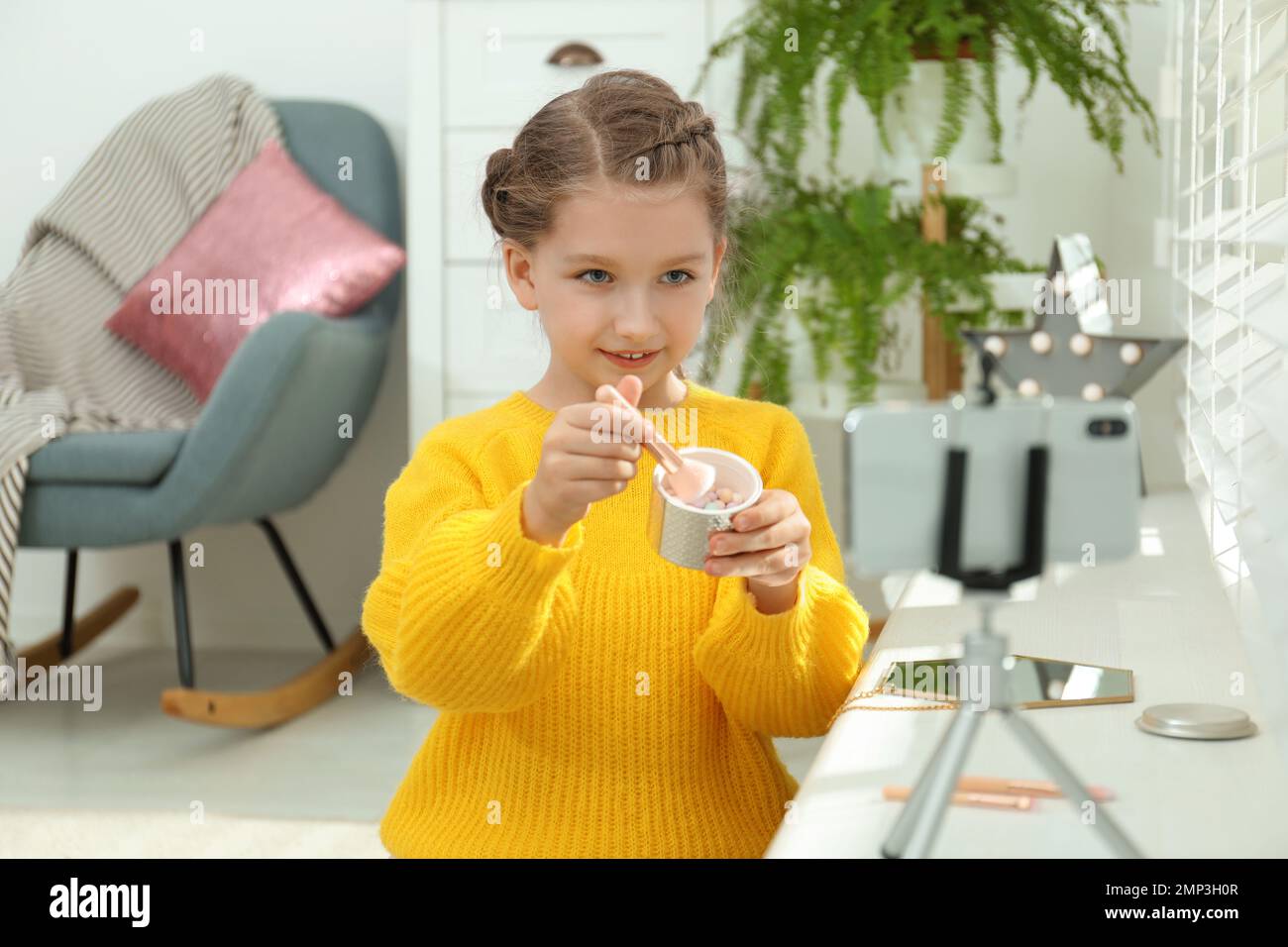 Cute little blogger with cosmetics recording video at home Stock Photo ...