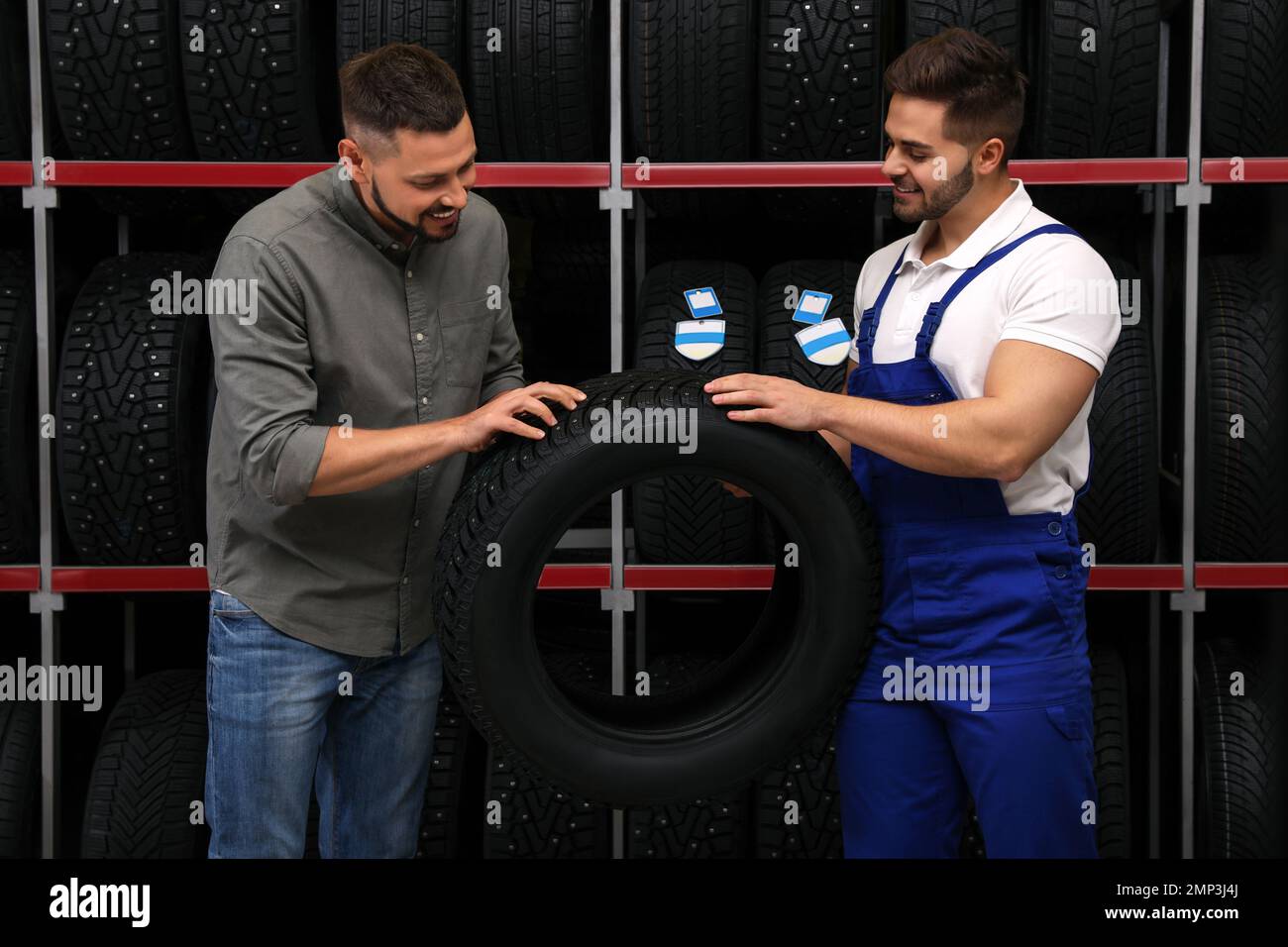 Mechanic helping client to choose car tire in auto store Stock Photo ...