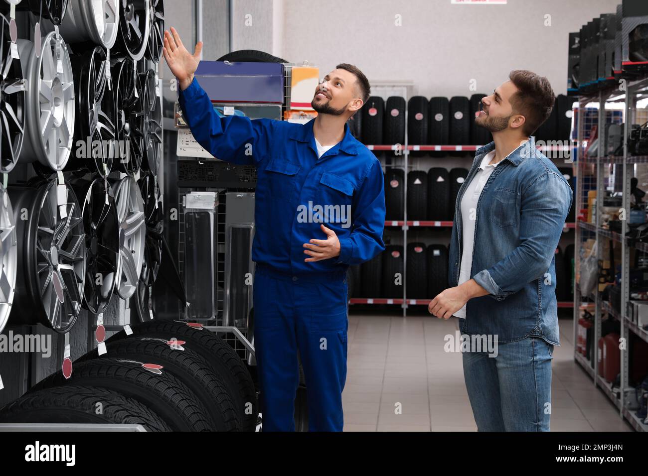 Male mechanic helping client to choose alloy wheel in auto store Stock ...