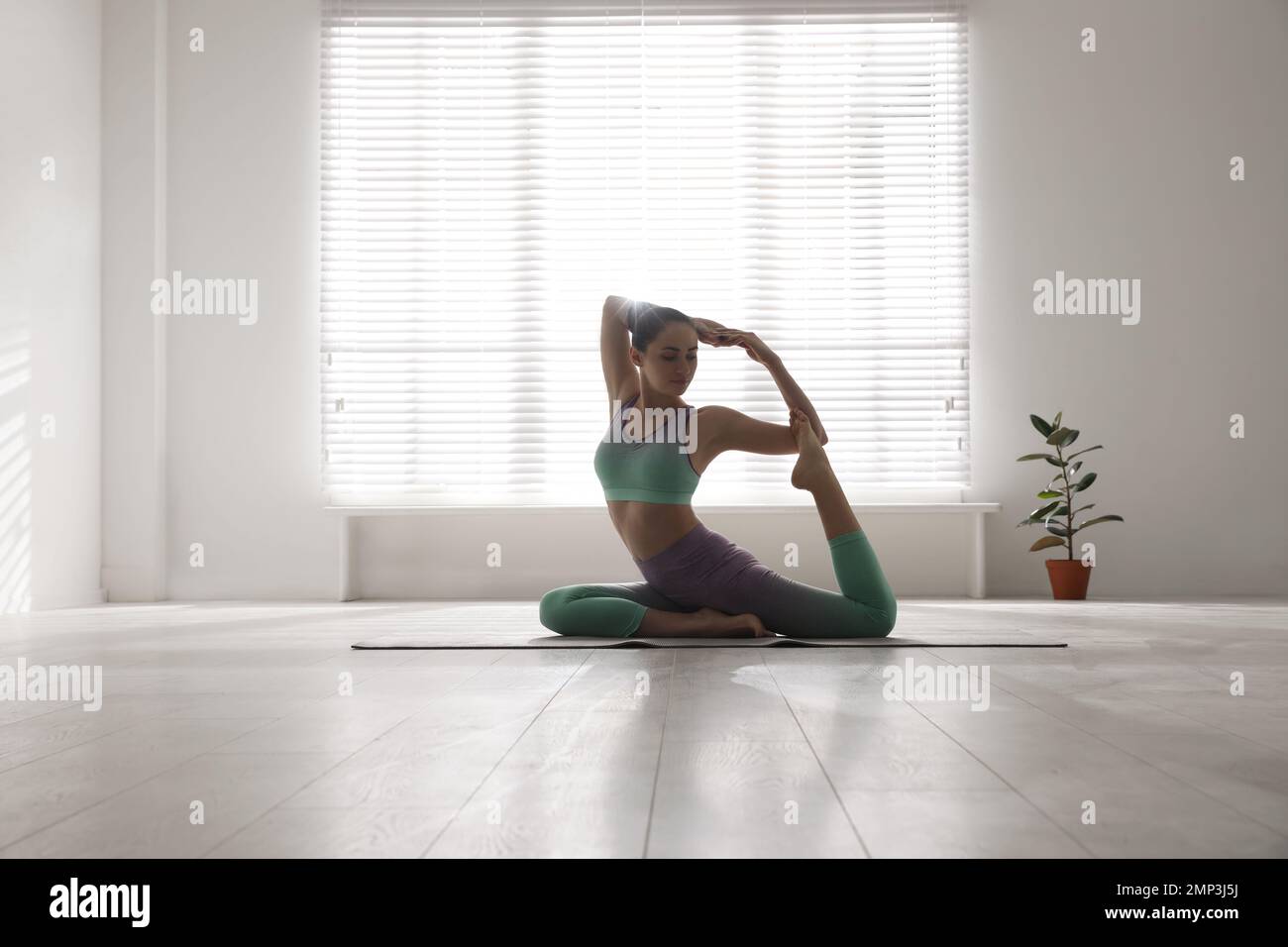 Woman practicing mermaid asana in yoga studio. Eka pada rajakapotasana ...
