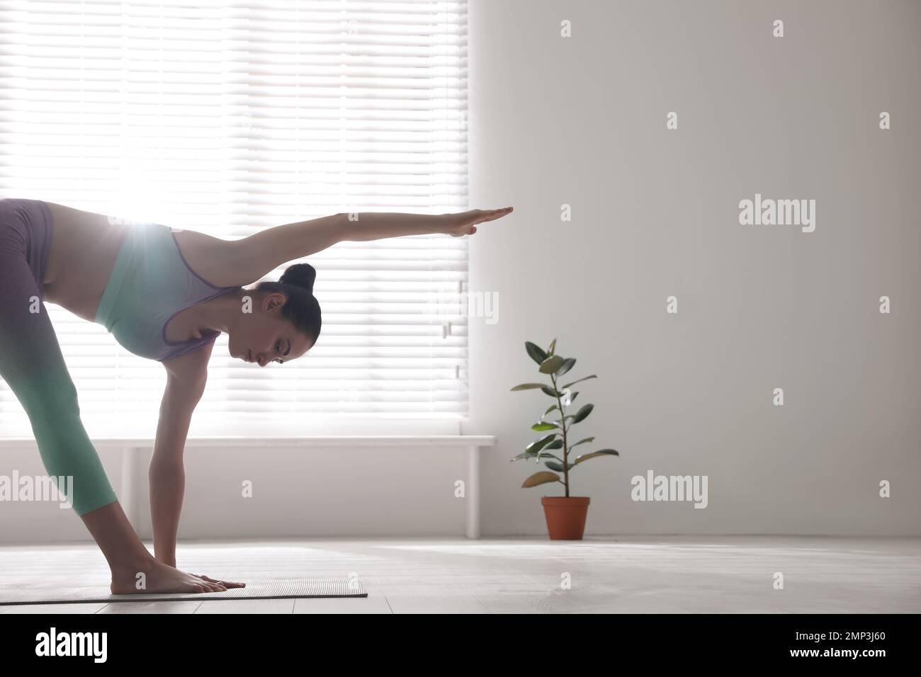 Young woman practicing extended triangle asana in yoga studio. Utthita ...