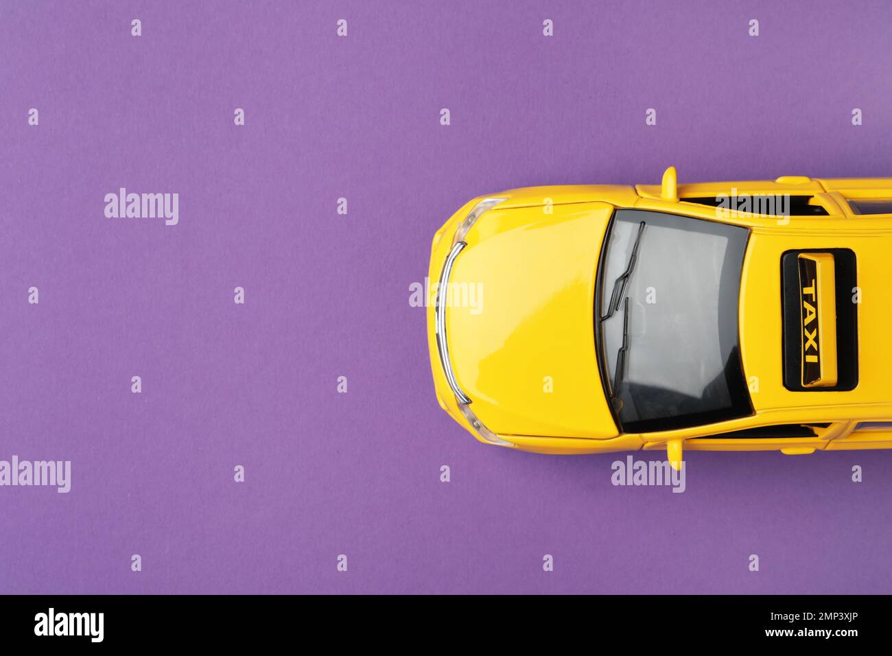 Yellow taxi car model on purple background, top view. Space for text ...