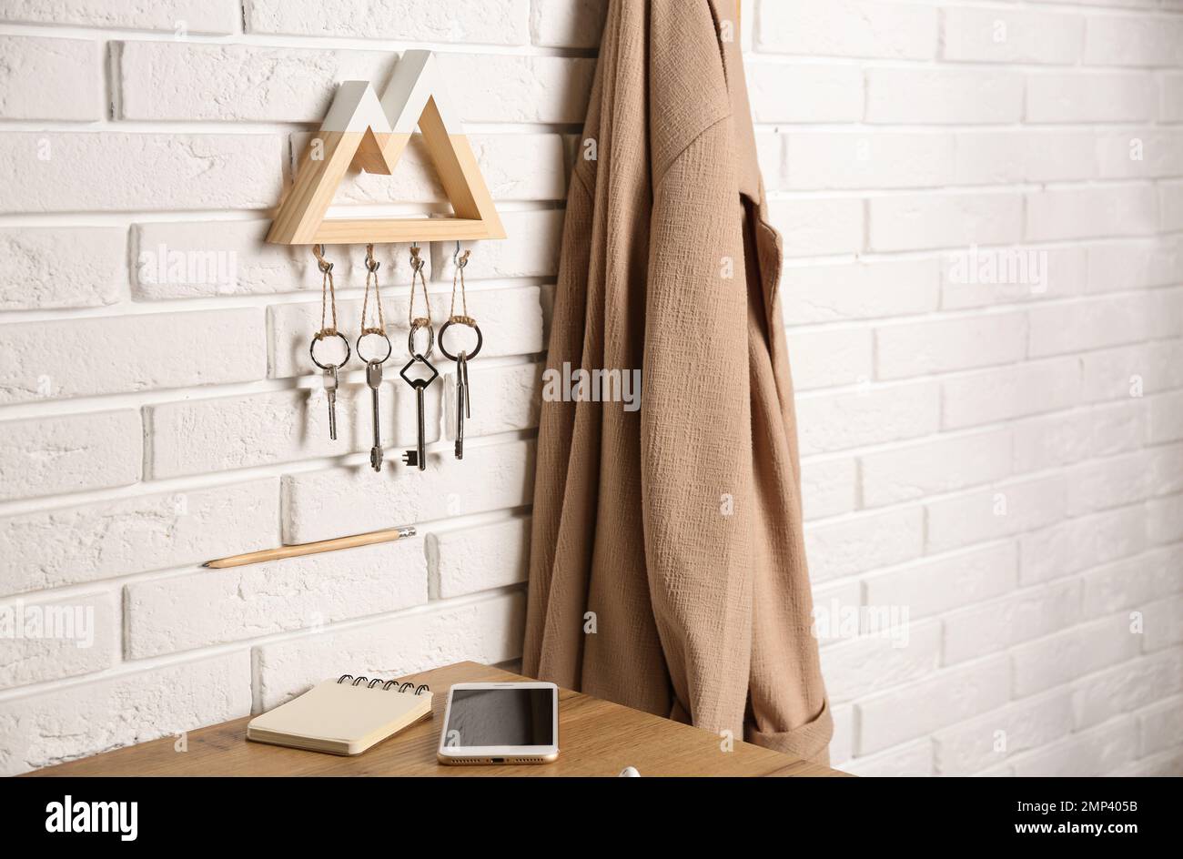 Wooden key holder on white brick wall indoors Stock Photo - Alamy
