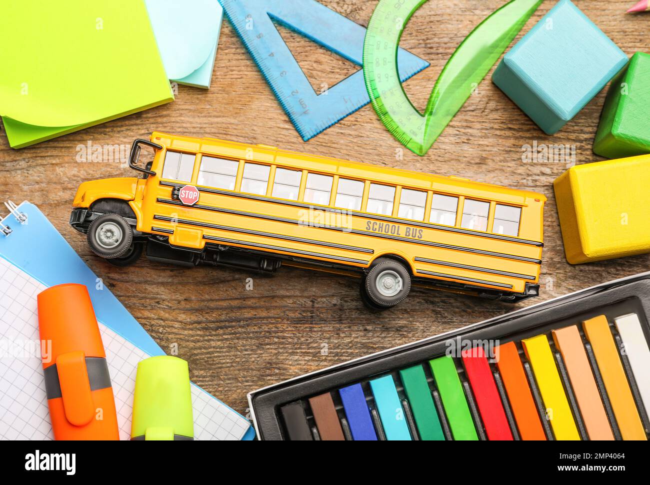 Flat lay composition with yellow school bus model on wooden background ...