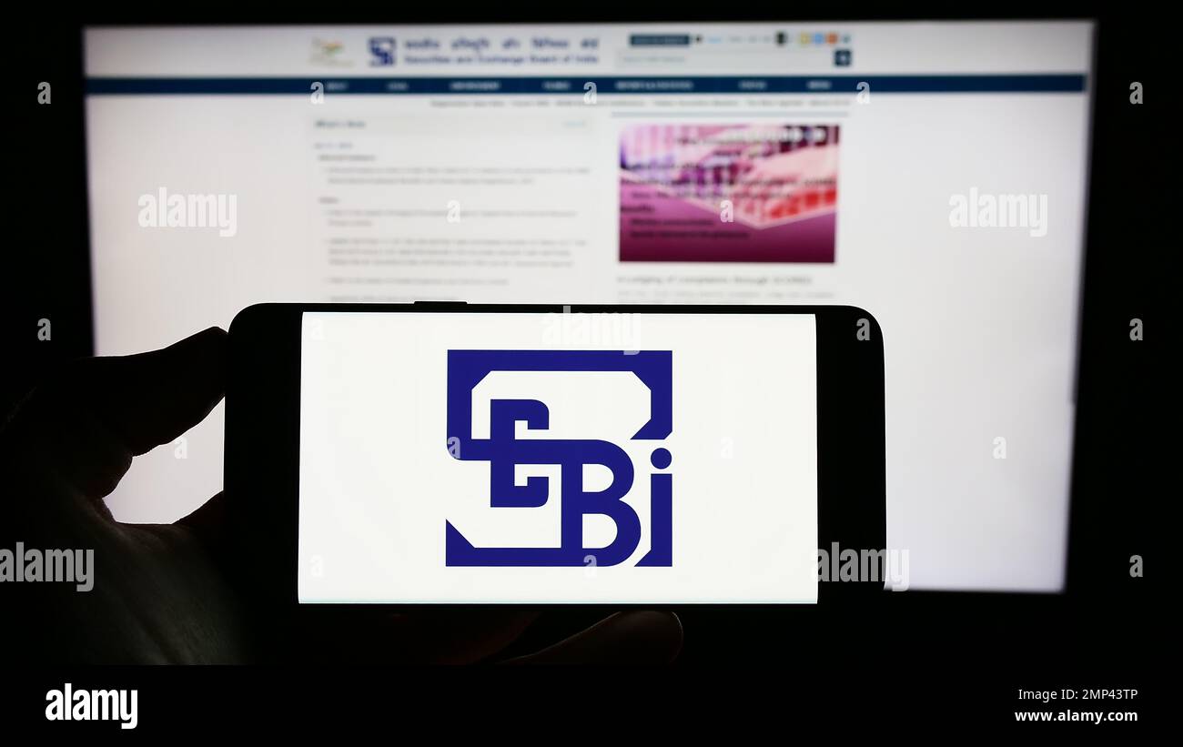Person holding mobile phone with logo of Securities and Exchange Board ...