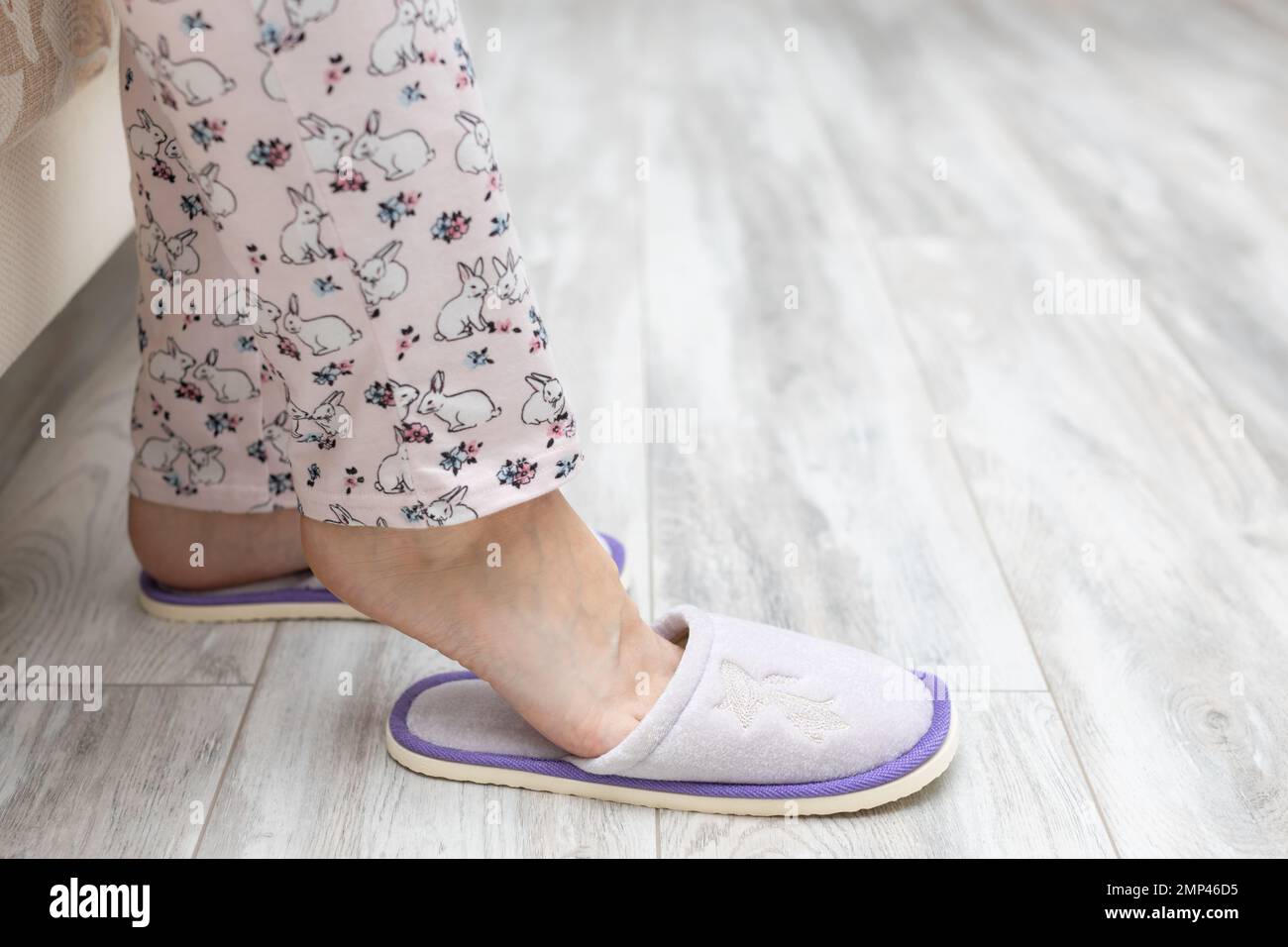 man puts on slippers sitting on the bed. man getting out of bed in the ...