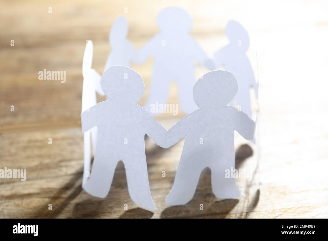 Paper people chain making circle on wooden background. Unity concept ...