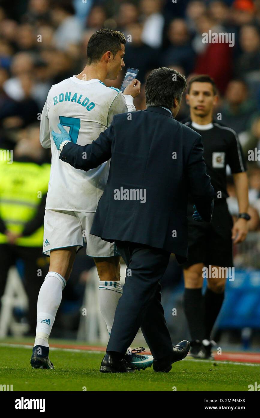 Real Madrid's Cristiano Ronaldo leaves the pitch as he uses a phone to ...