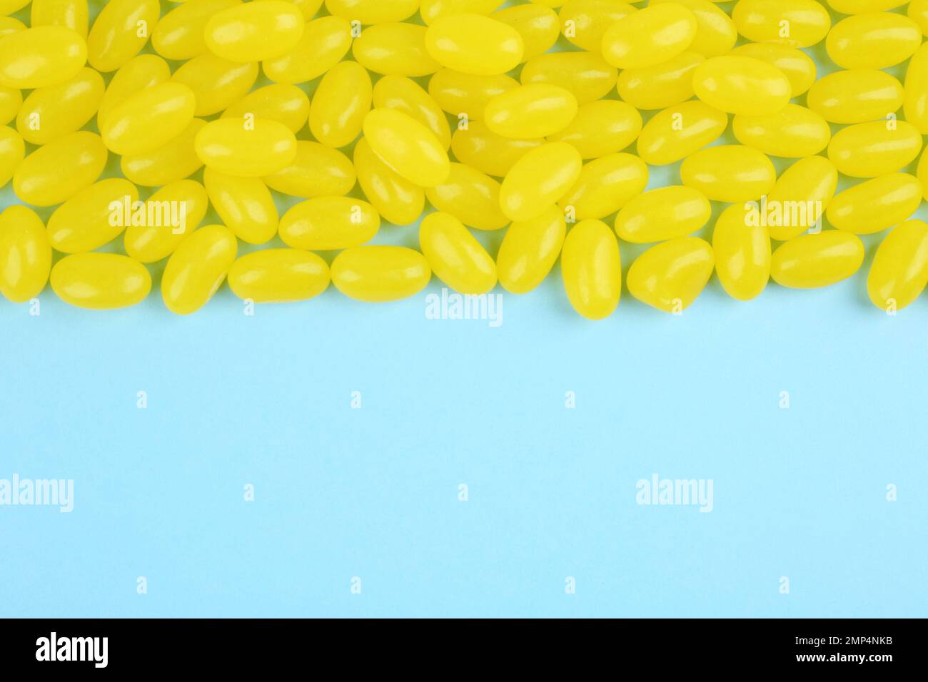 Many delicious lemon jelly beans on light blue background, flat lay ...