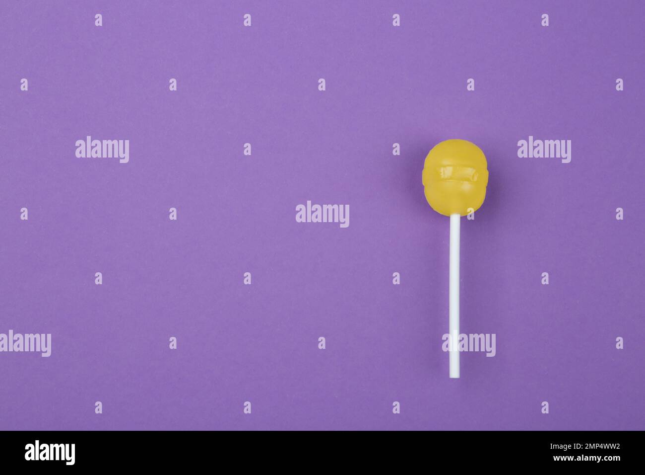 Tasty lemon lollipop on purple background, top view. Space for text ...