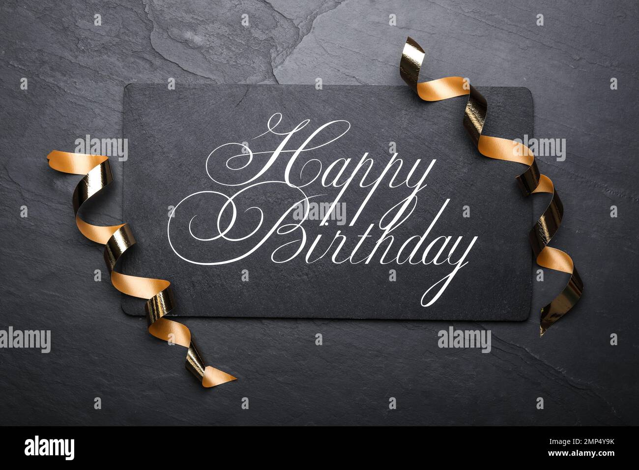 Slate board with greeting HAPPY BIRTHDAY and serpentine streamers on ...
