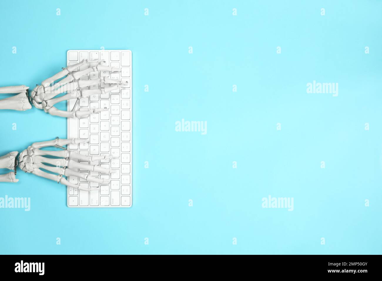 Human skeleton using computer keyboard on light blue background, top ...