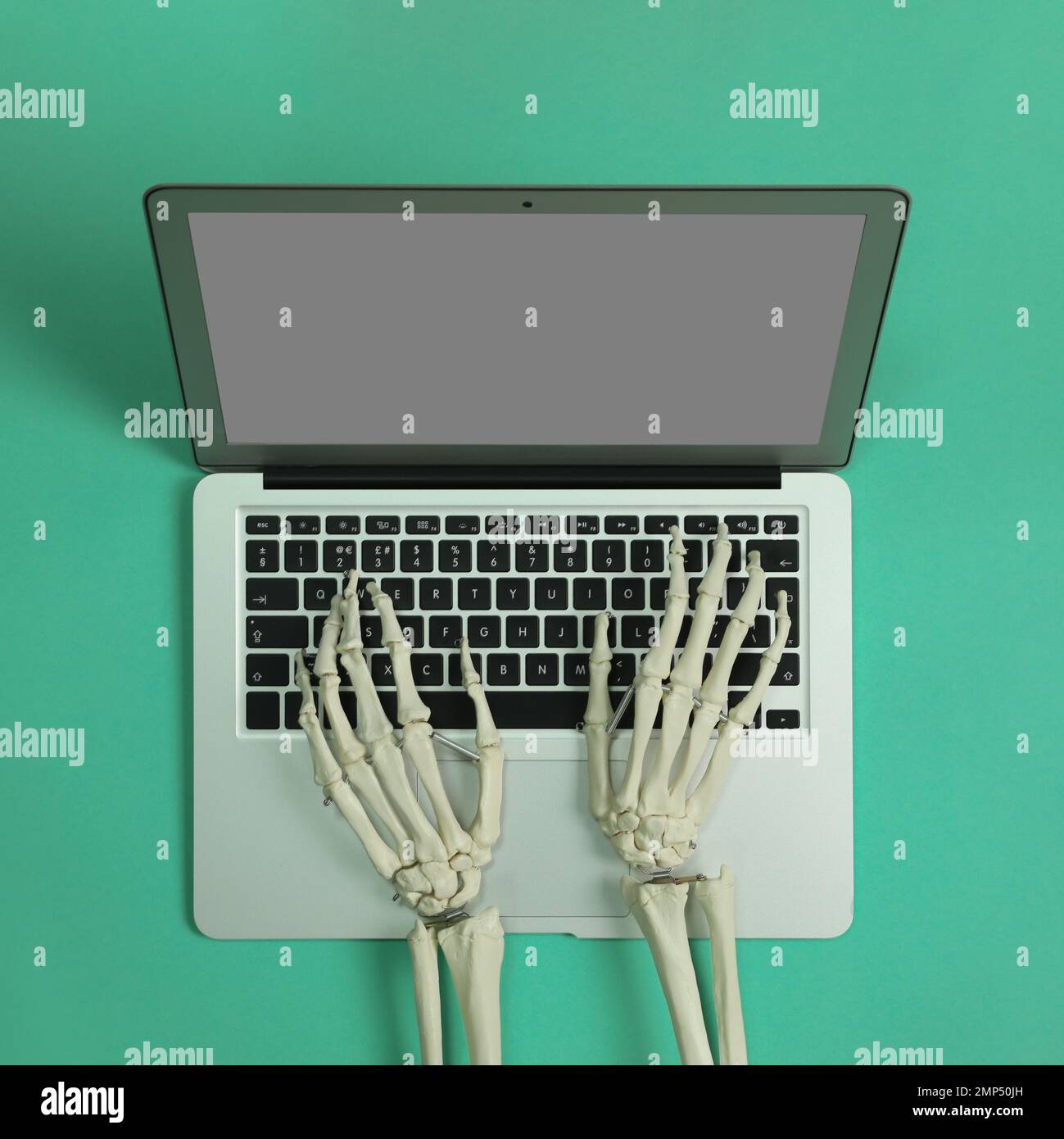 Human skeleton using laptop on green background, top view Stock Photo ...