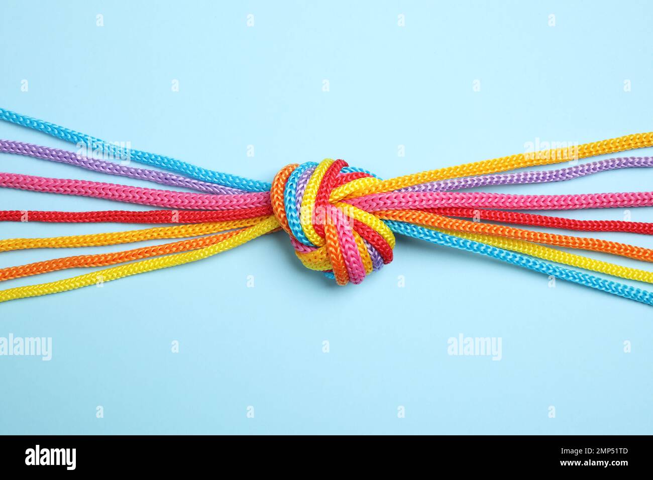 Colorful ropes tied together on light blue background, top view. Unity ...