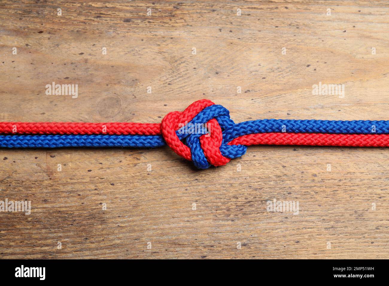 Colorful ropes tied together on wooden background, top view. Unity ...