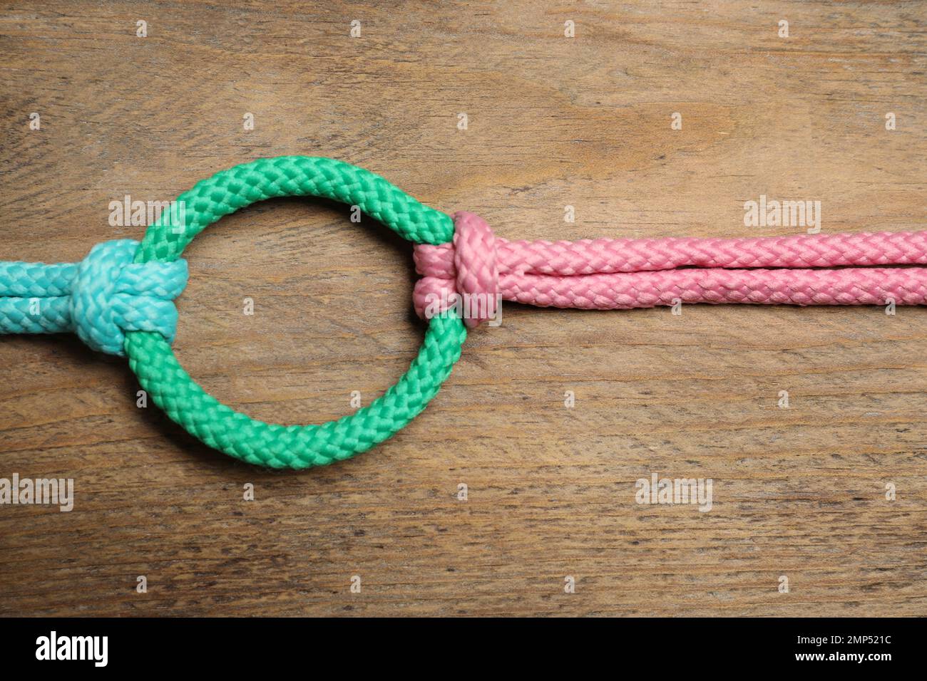 Colorful ropes tied together on wooden background, top view. Unity ...