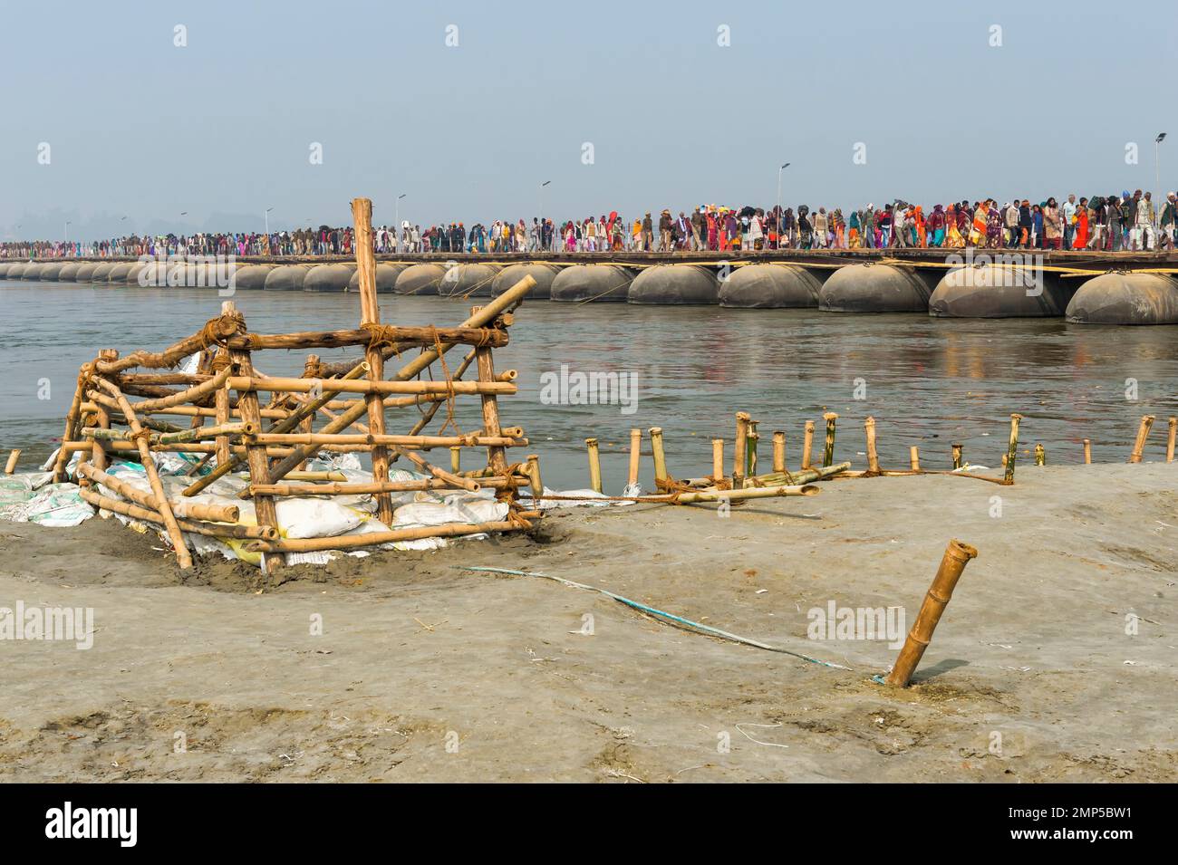 Pilgrims crossing the Ganges river on a temporary pontoon bridge ...