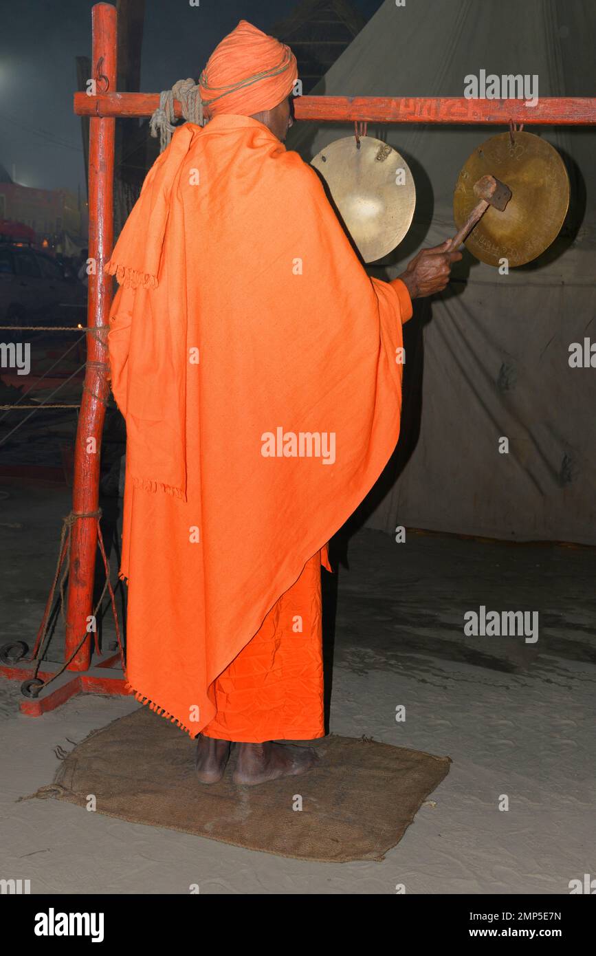 Hindu priest in saffron cloth ringing the bell at night, Allahabad ...