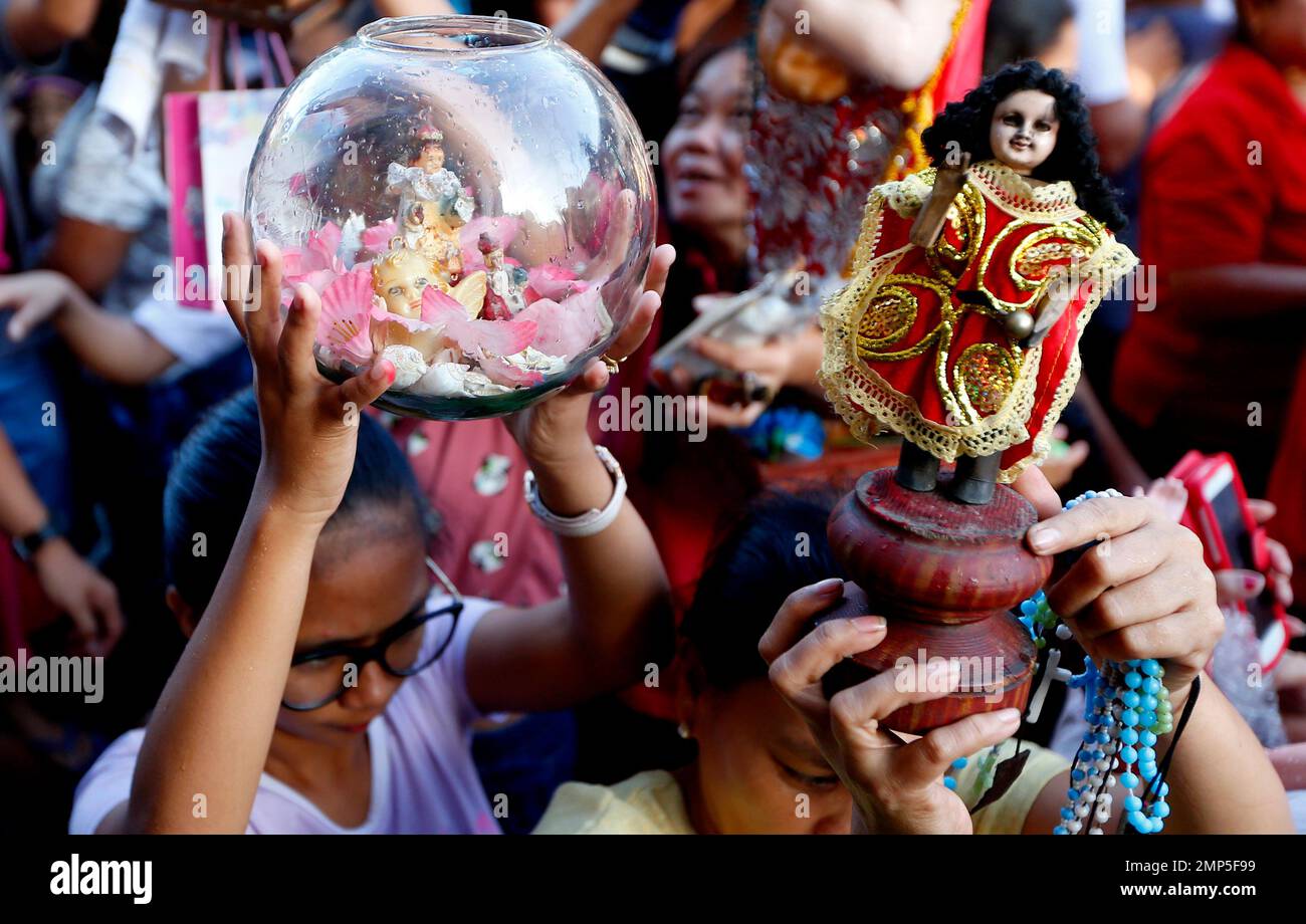 A Roman Catholic devotee, left, raises her fish bowl with images of the ...