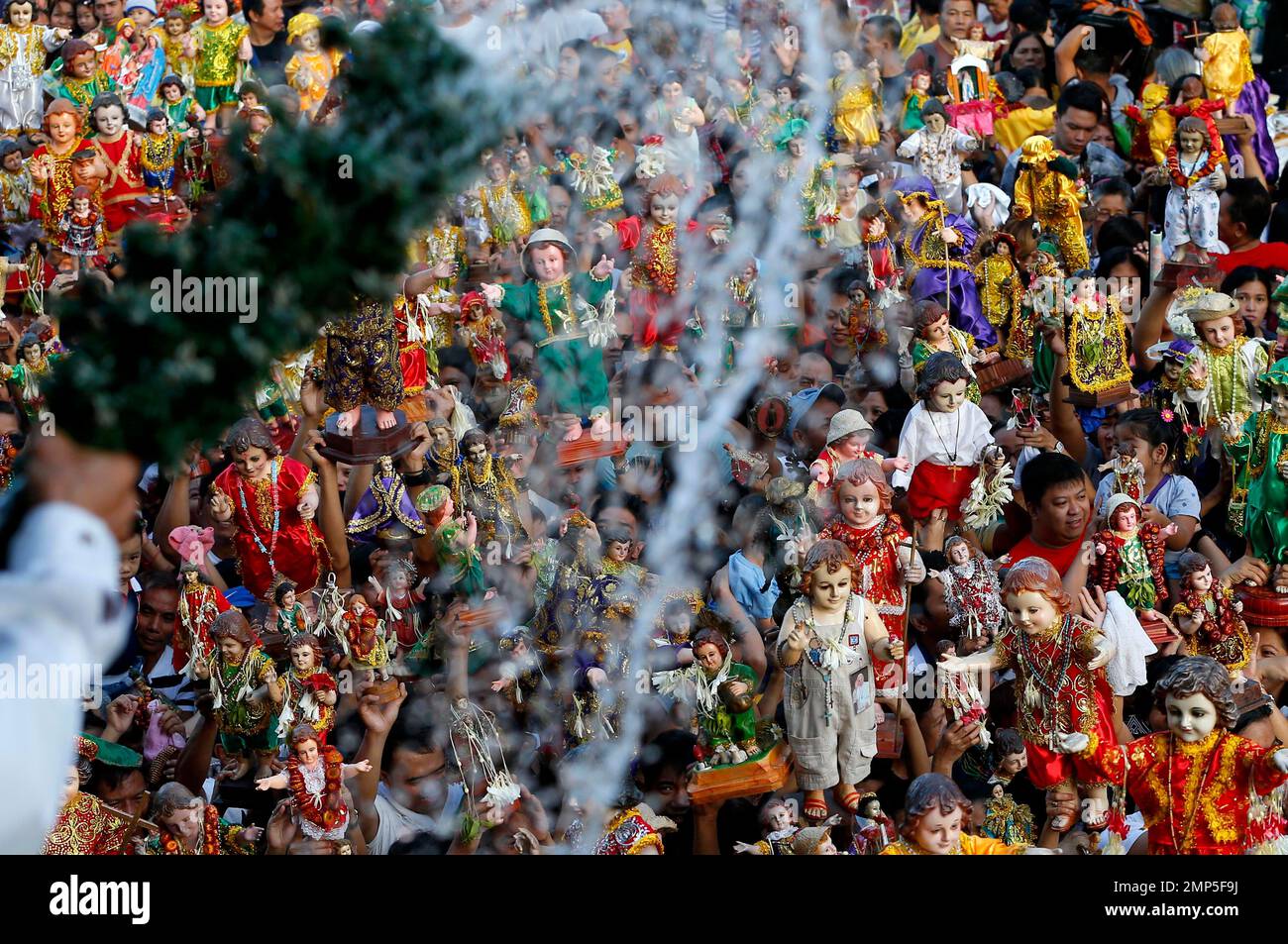 A Roman Catholic lay leader sprinkles with holy water images of the ...