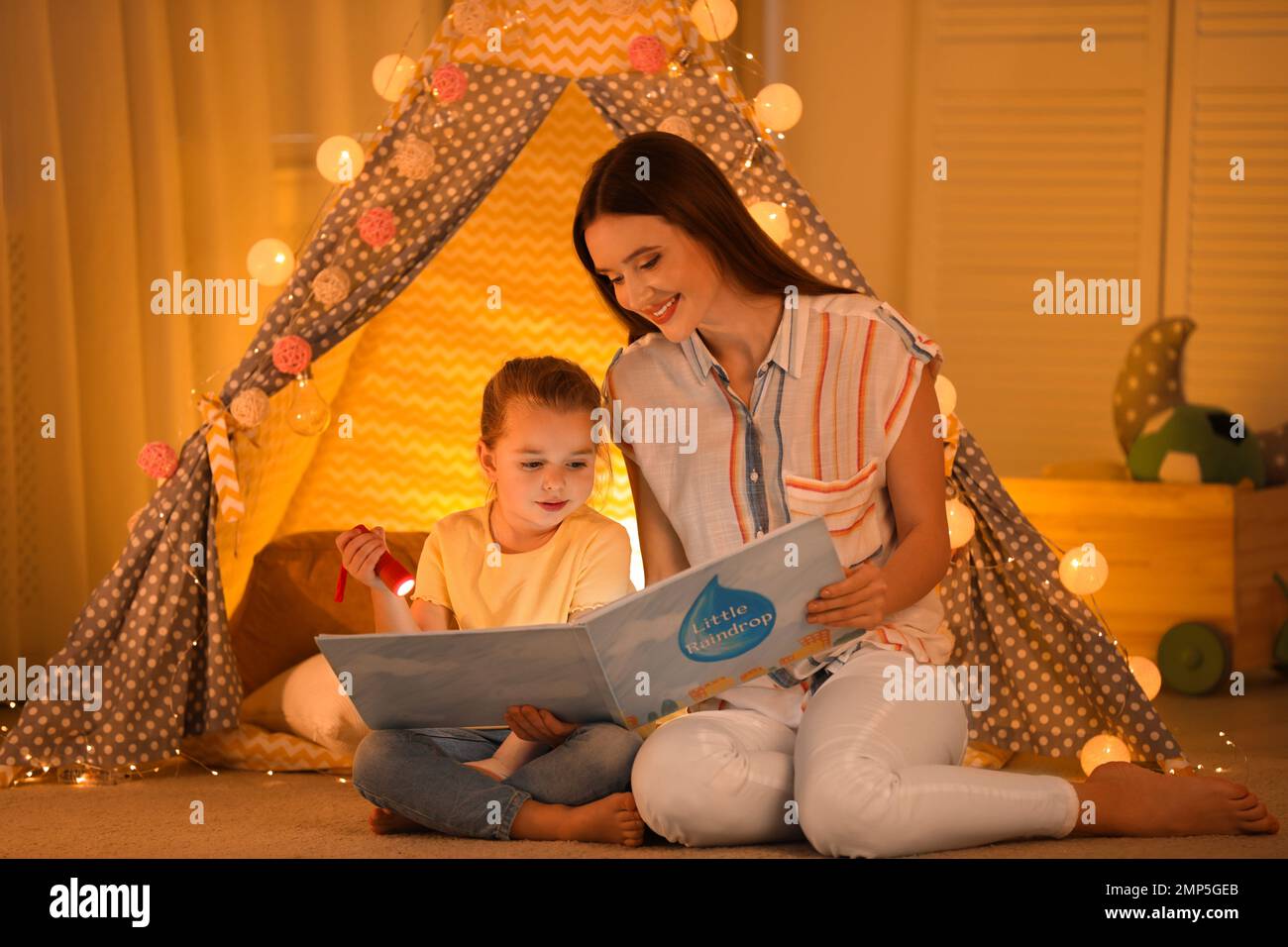 Mother and daughter with flashlight reading book at home Stock Photo ...