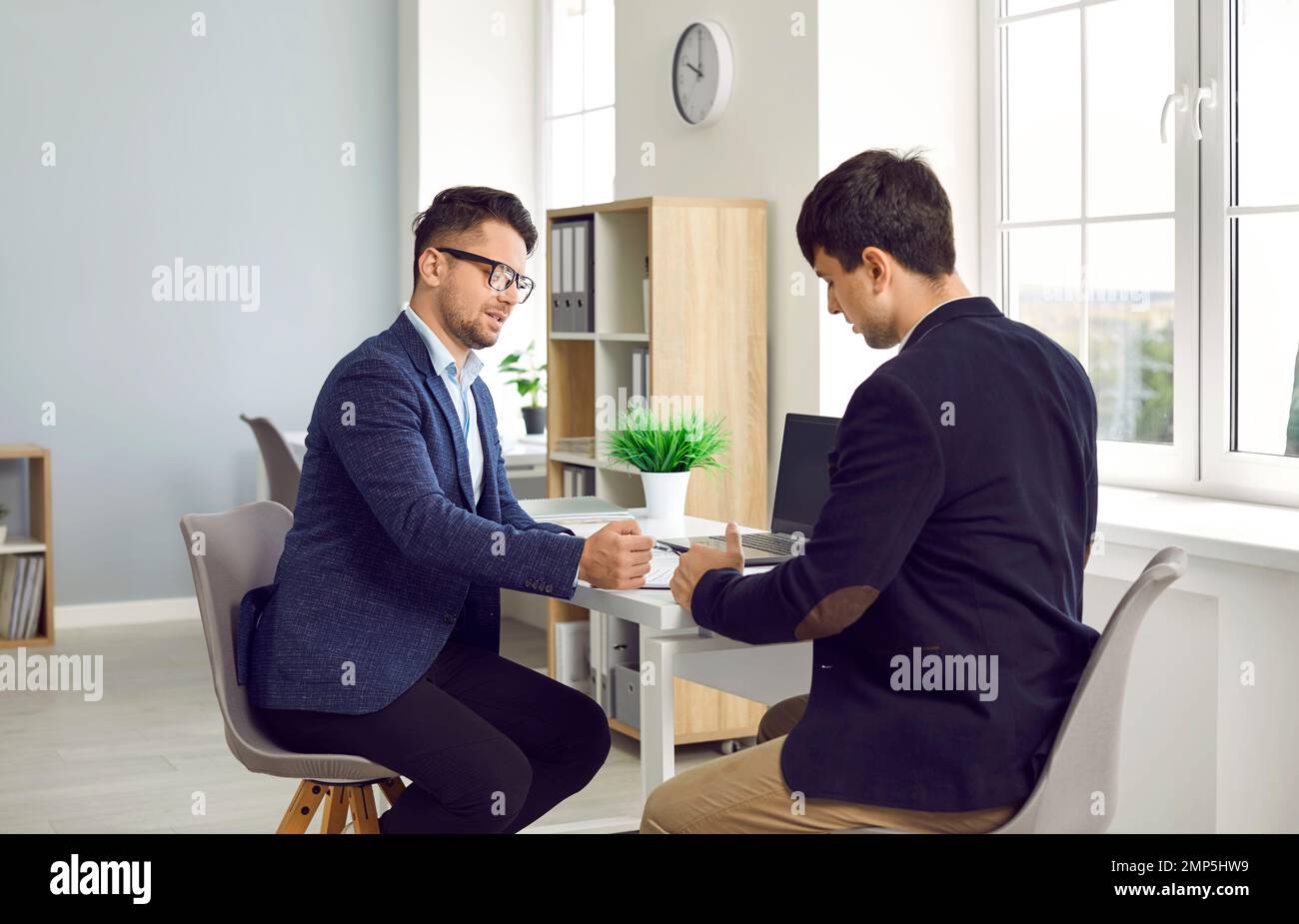 Confident businessman discussing terms of contract with male client and ...