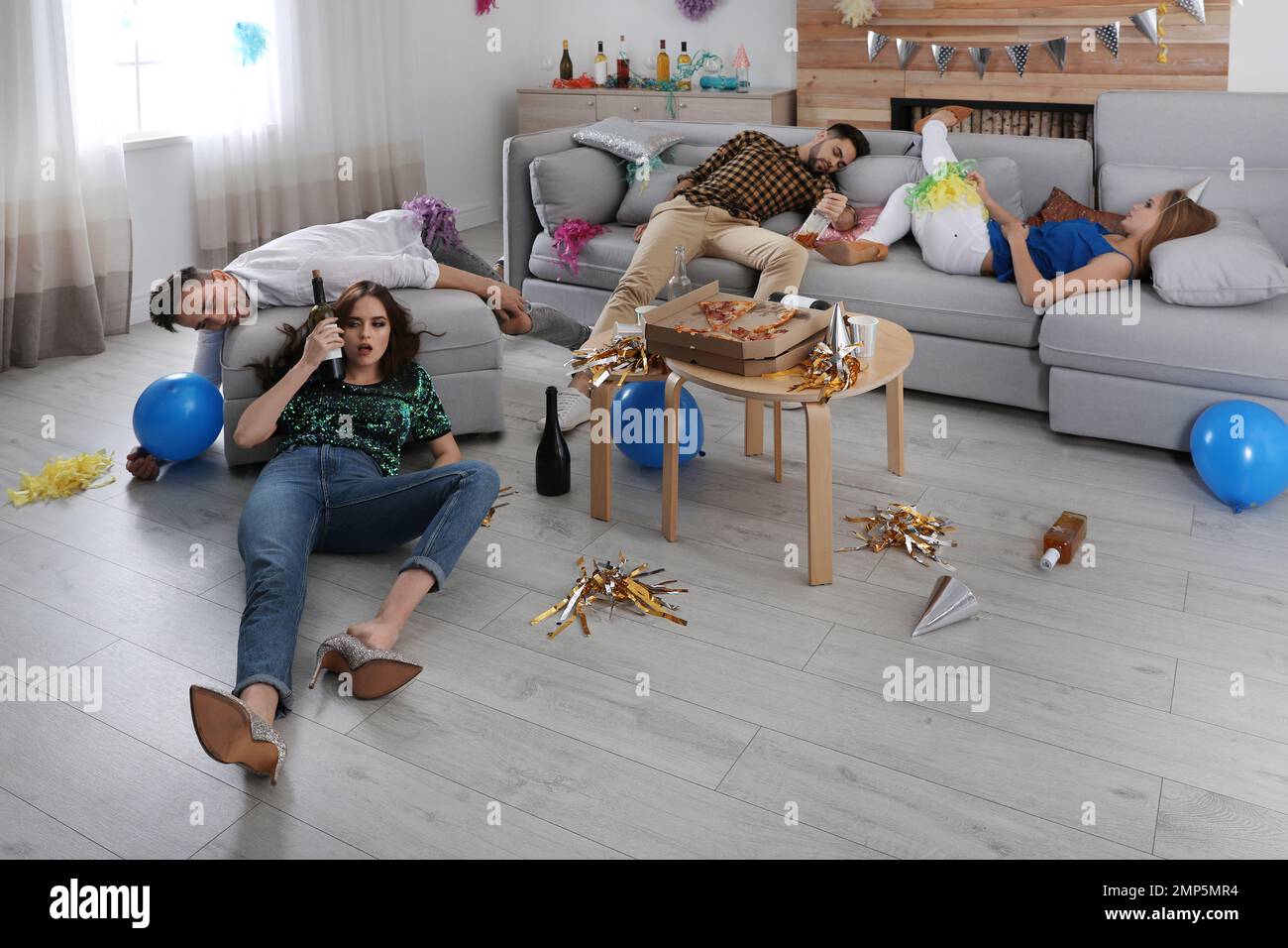 Drunk friends suffering from hangover in messy room after party Stock ...