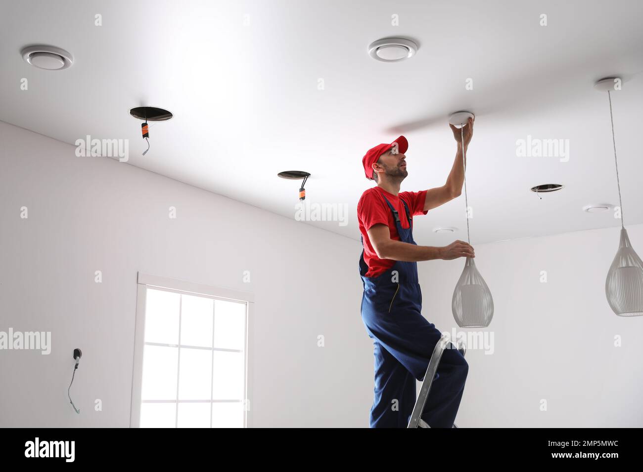 Worker installing lamp on stretch ceiling indoors Stock Photo - Alamy