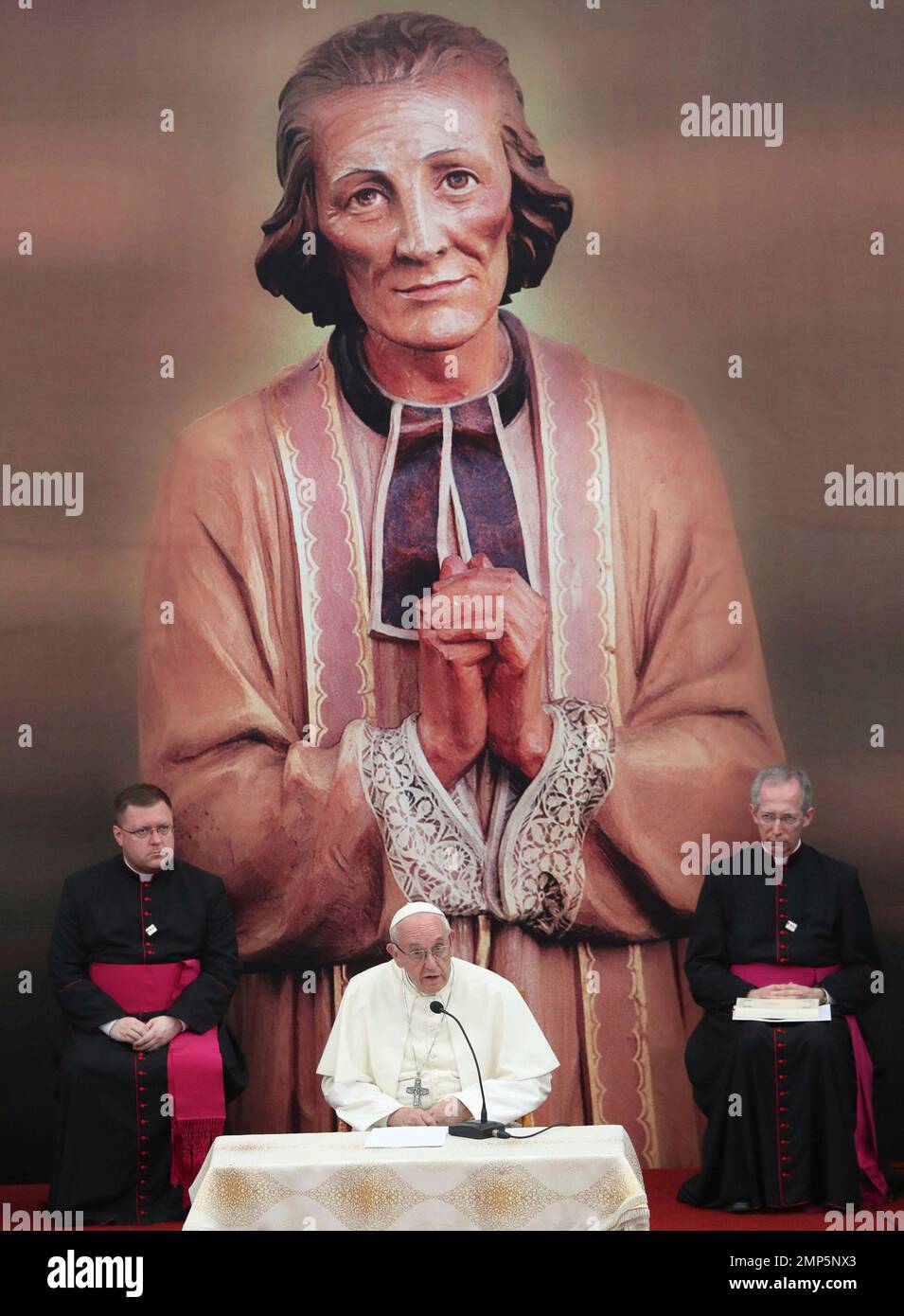Sitting against a backdrop depicting St. John Vianney, patron saint of ...