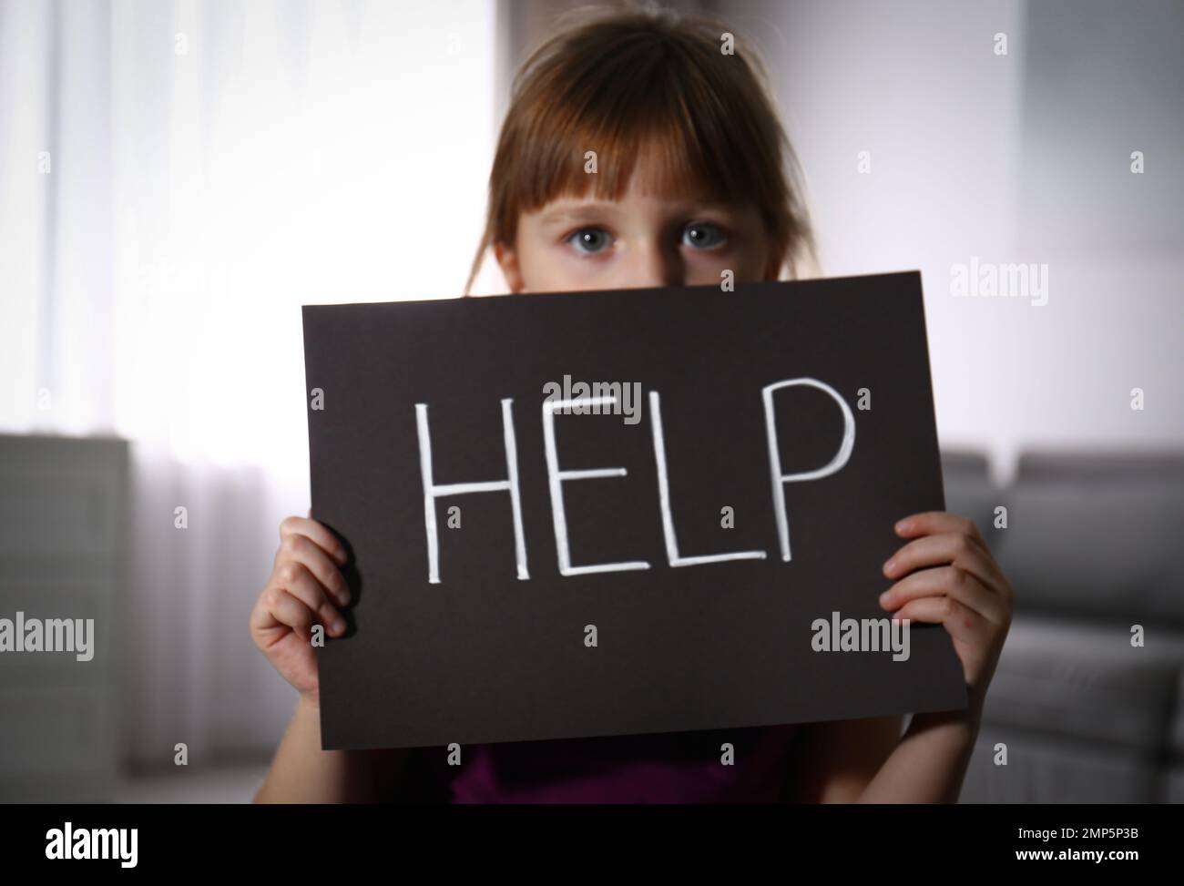 Abused little girl with sign HELP indoors. Domestic violence concept ...