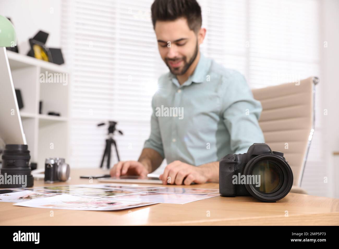 Professional photographer working at table in office, focus on camera ...