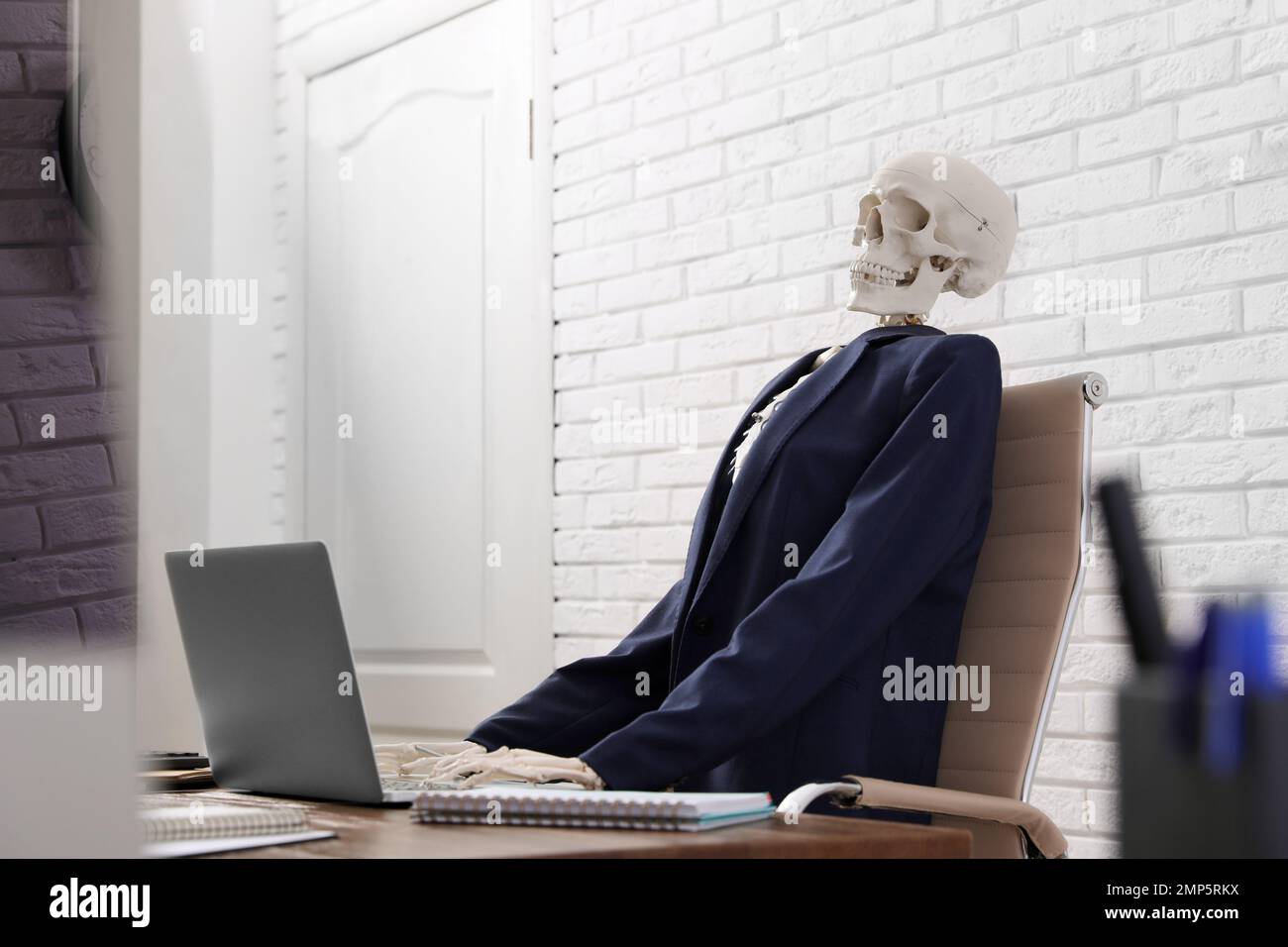 Human skeleton in suit using laptop at table in office Stock Photo - Alamy