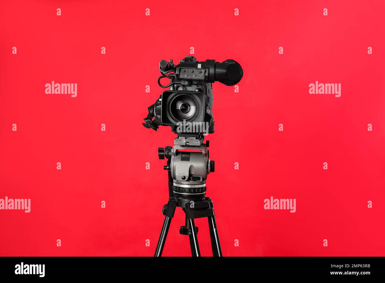 Modern professional video camera on red background Stock Photo - Alamy